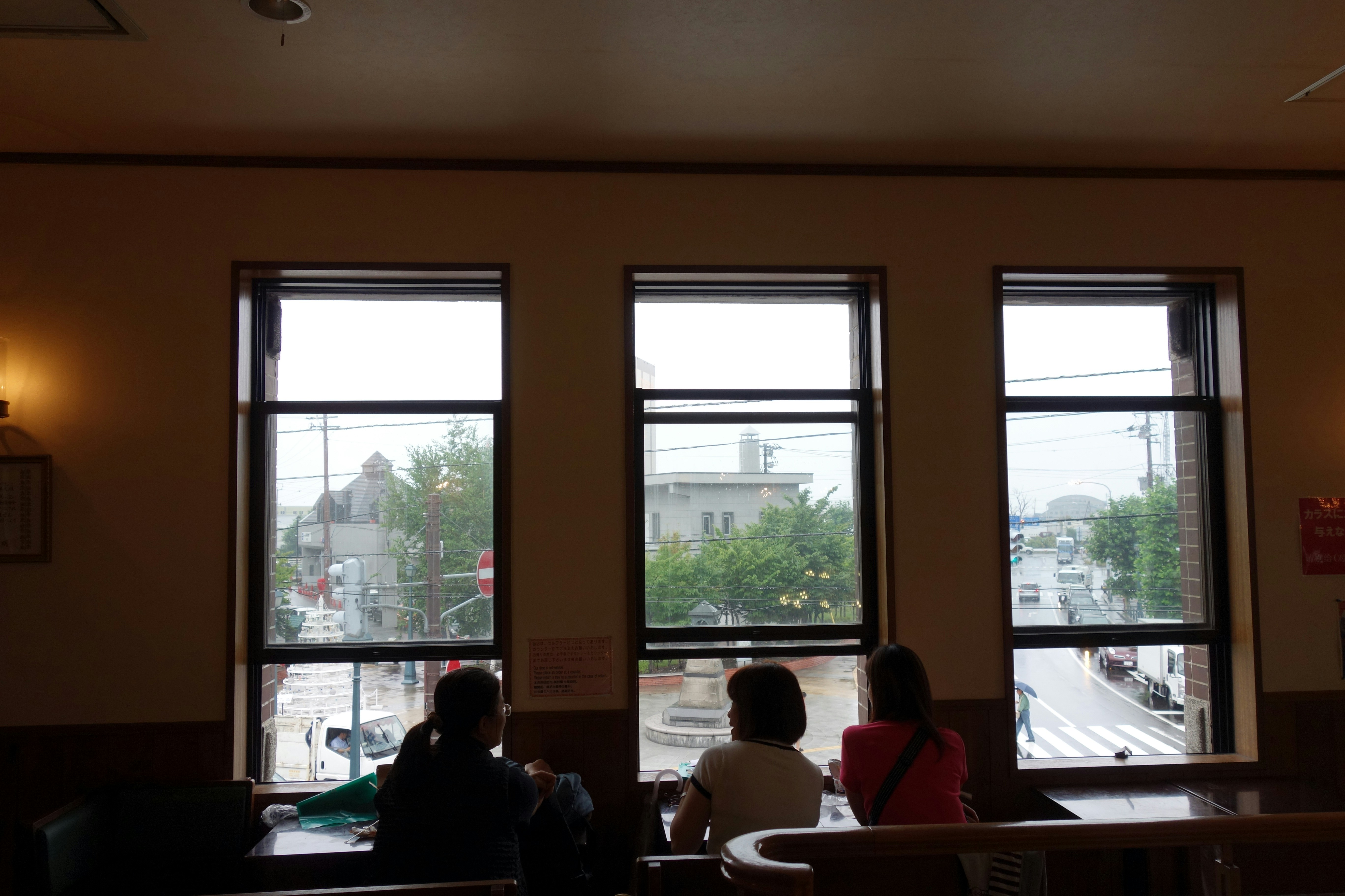 Three people sit facing three windows