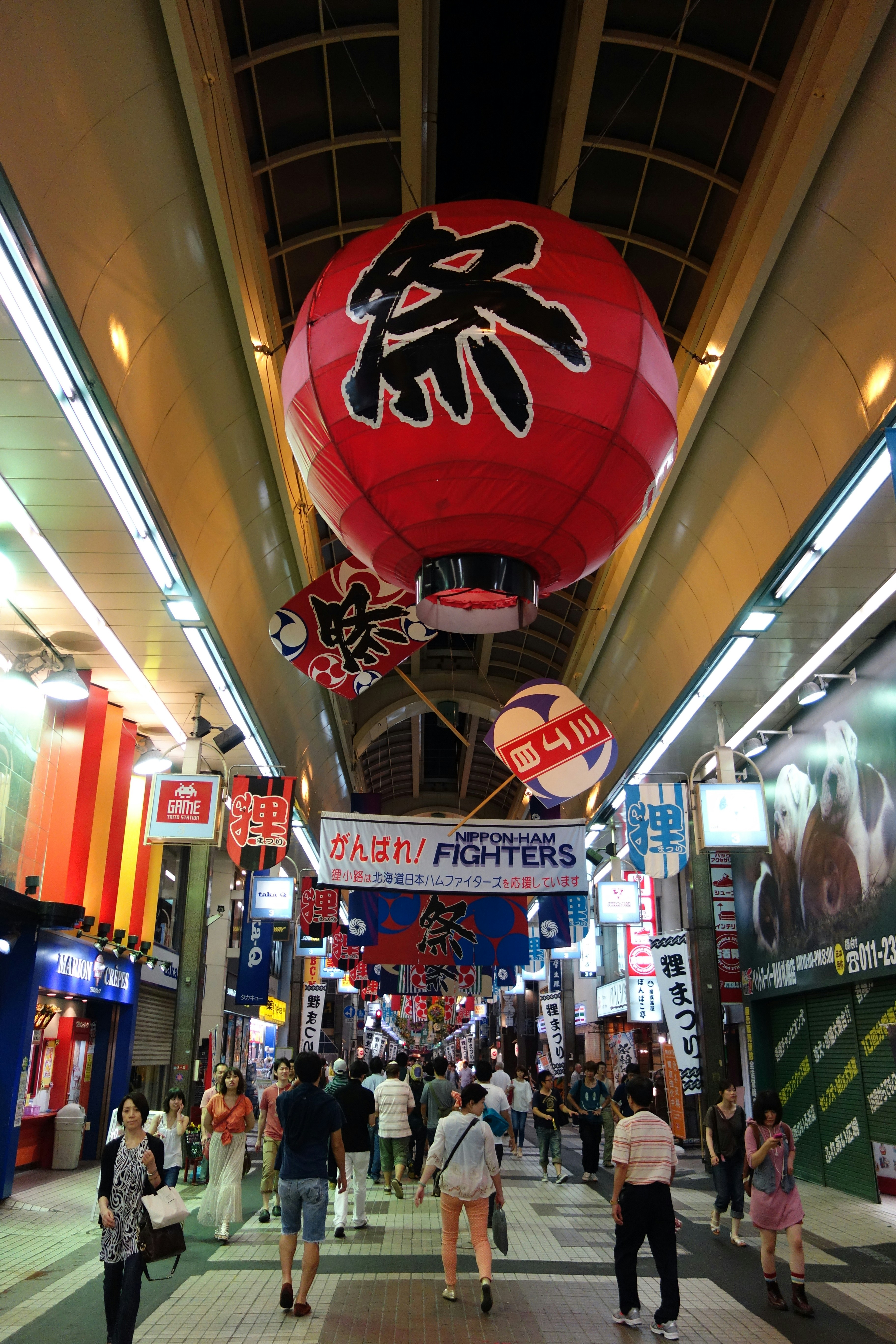 Giant red lantern floats above a bustling japanese street.