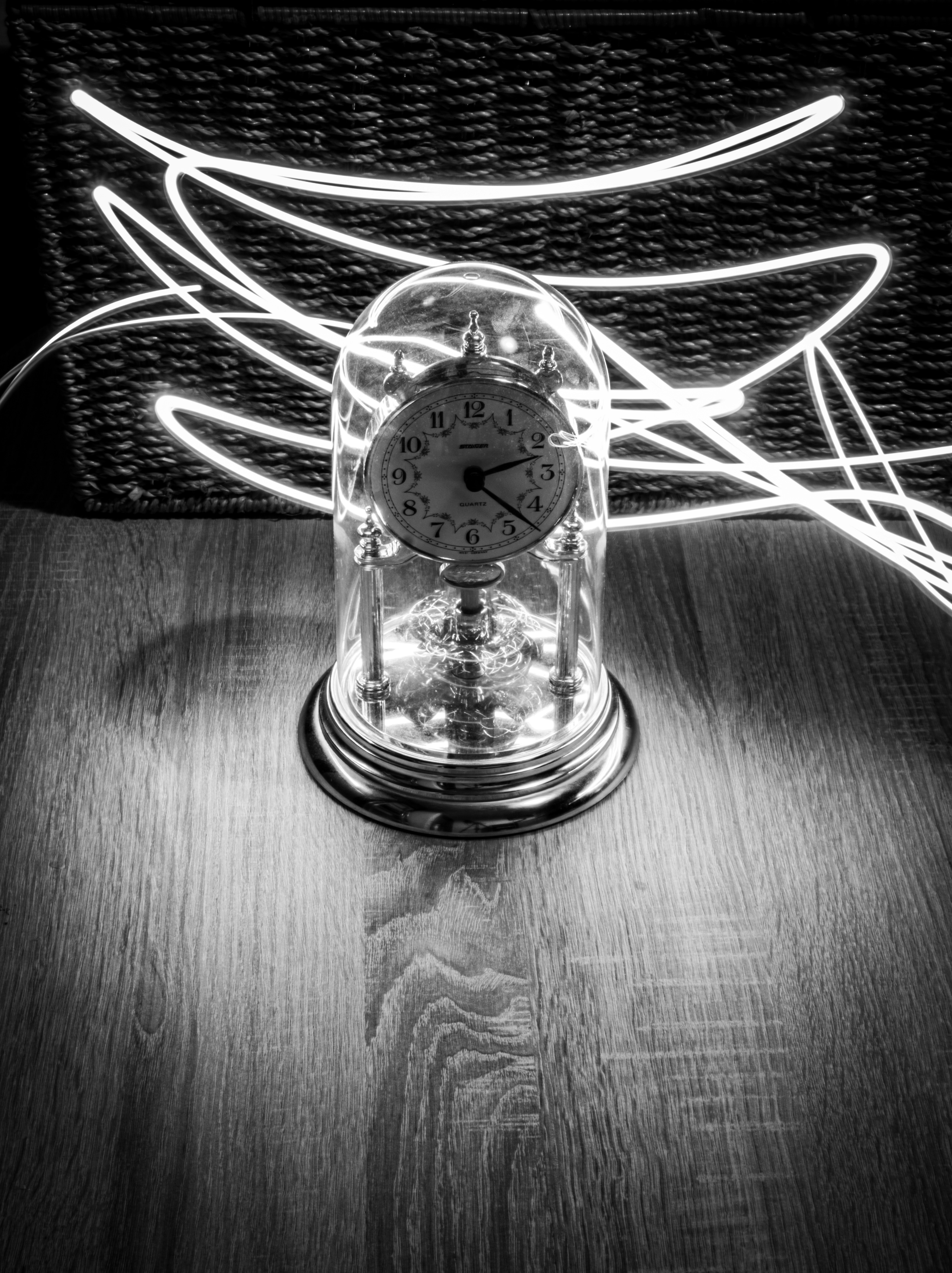 A vintage clock encased in glass, surrounded by swirling light trails creating a dynamic contrast against a dark background.