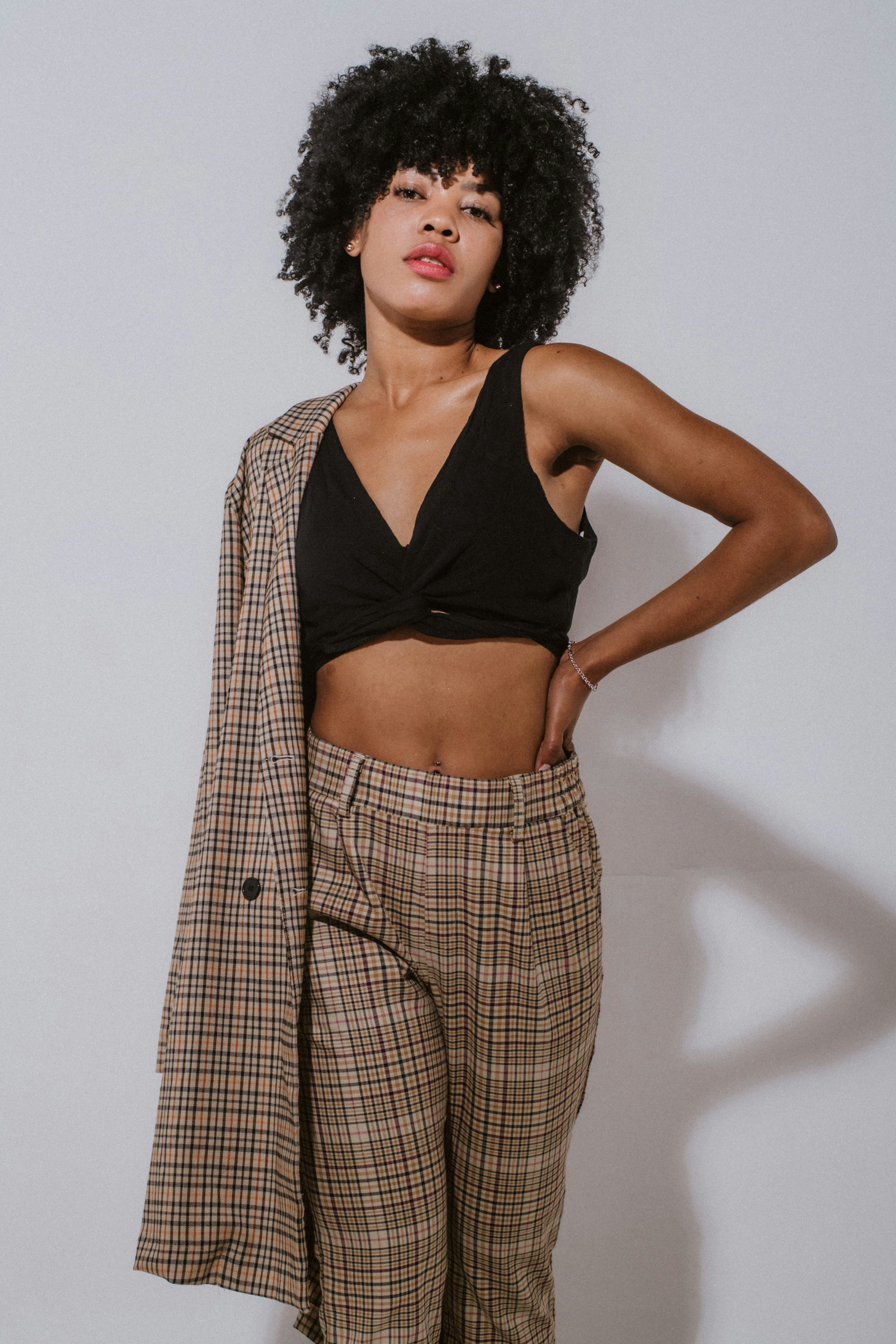 Woman in plaid pants and black top with jacket.