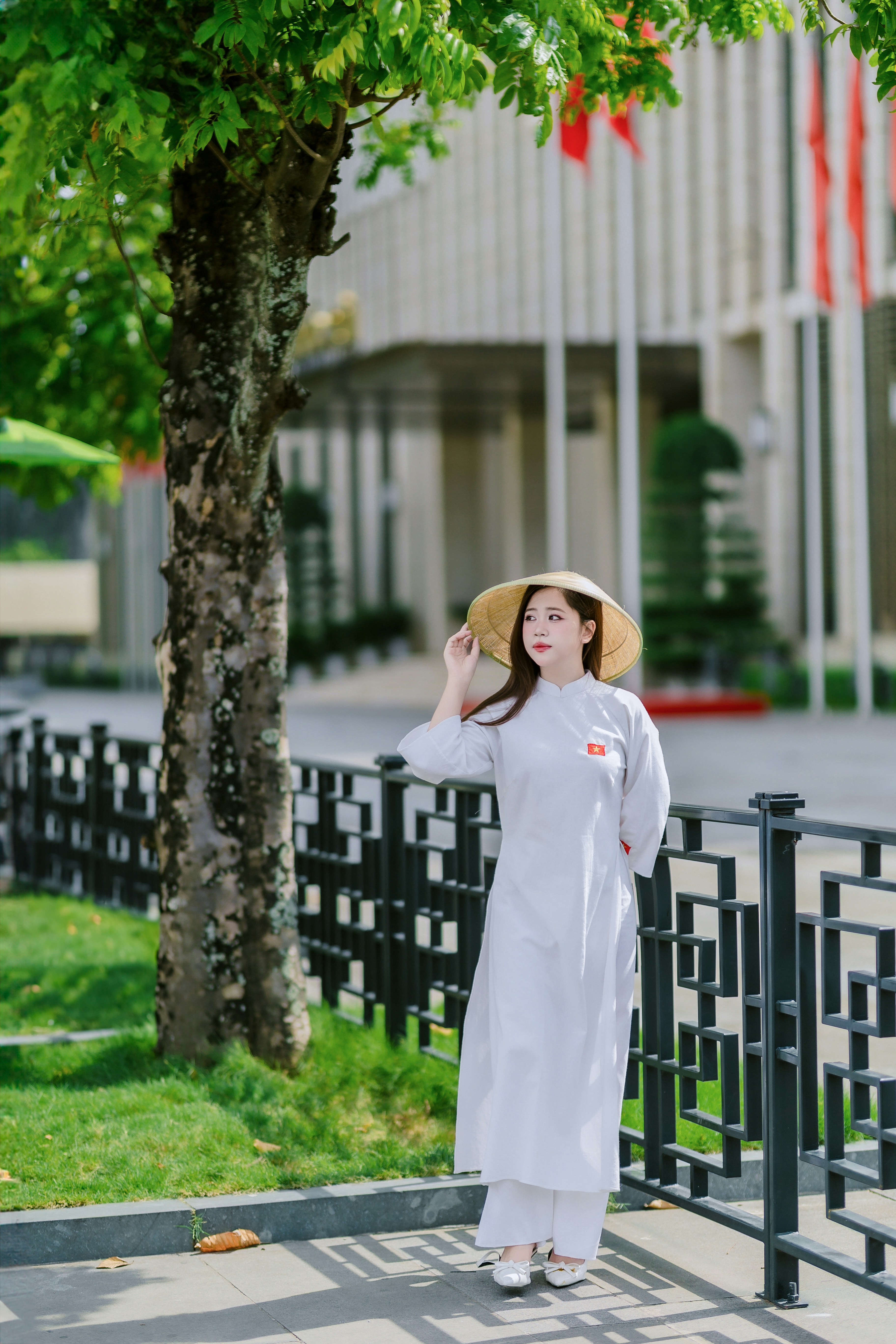 Vietnamese girl in ao dai celebrates national day | Young woman in traditional white dress and conical hat.