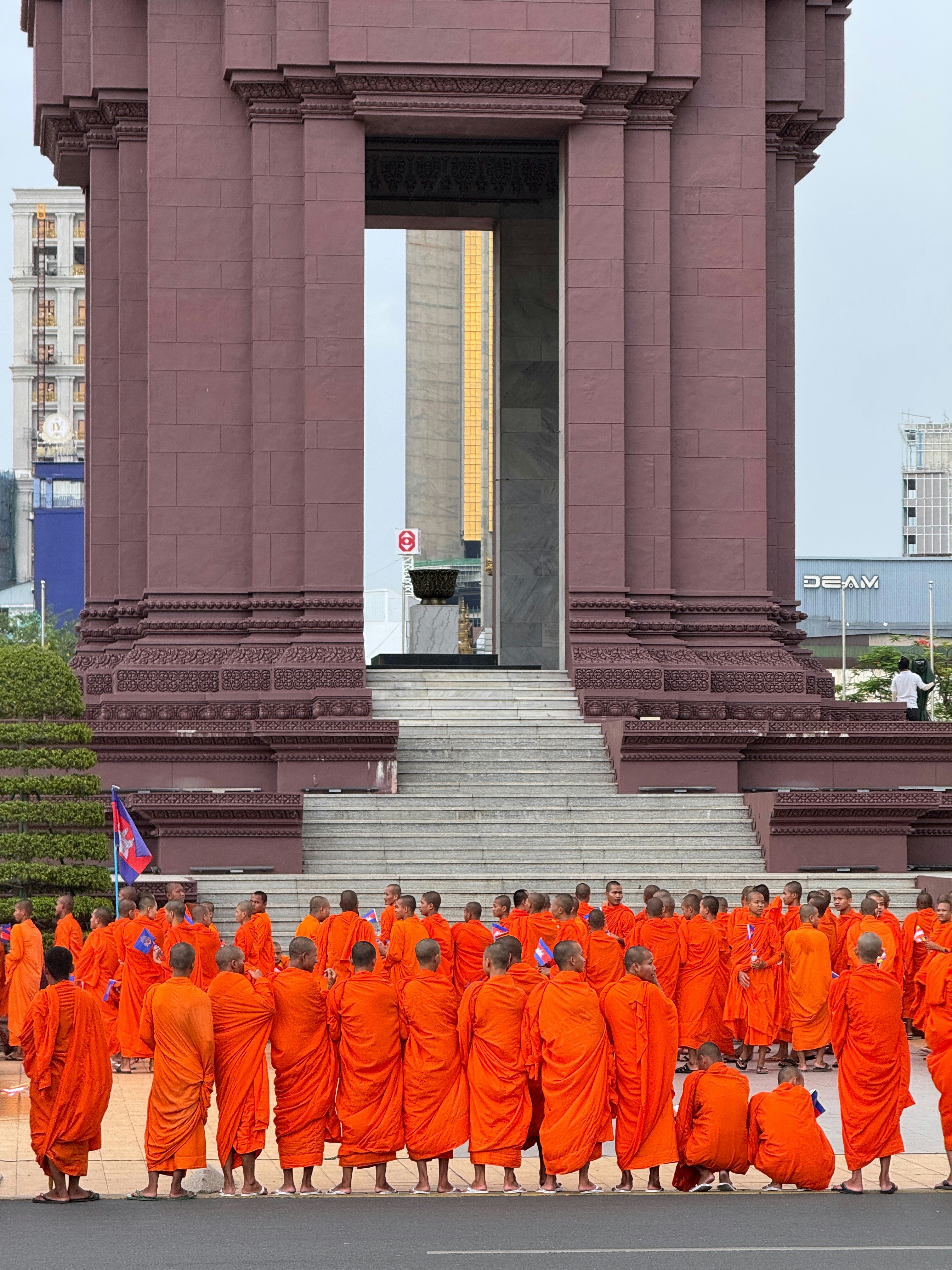 Cambodia Need Peace | Monks in orange robes gather at a monument.