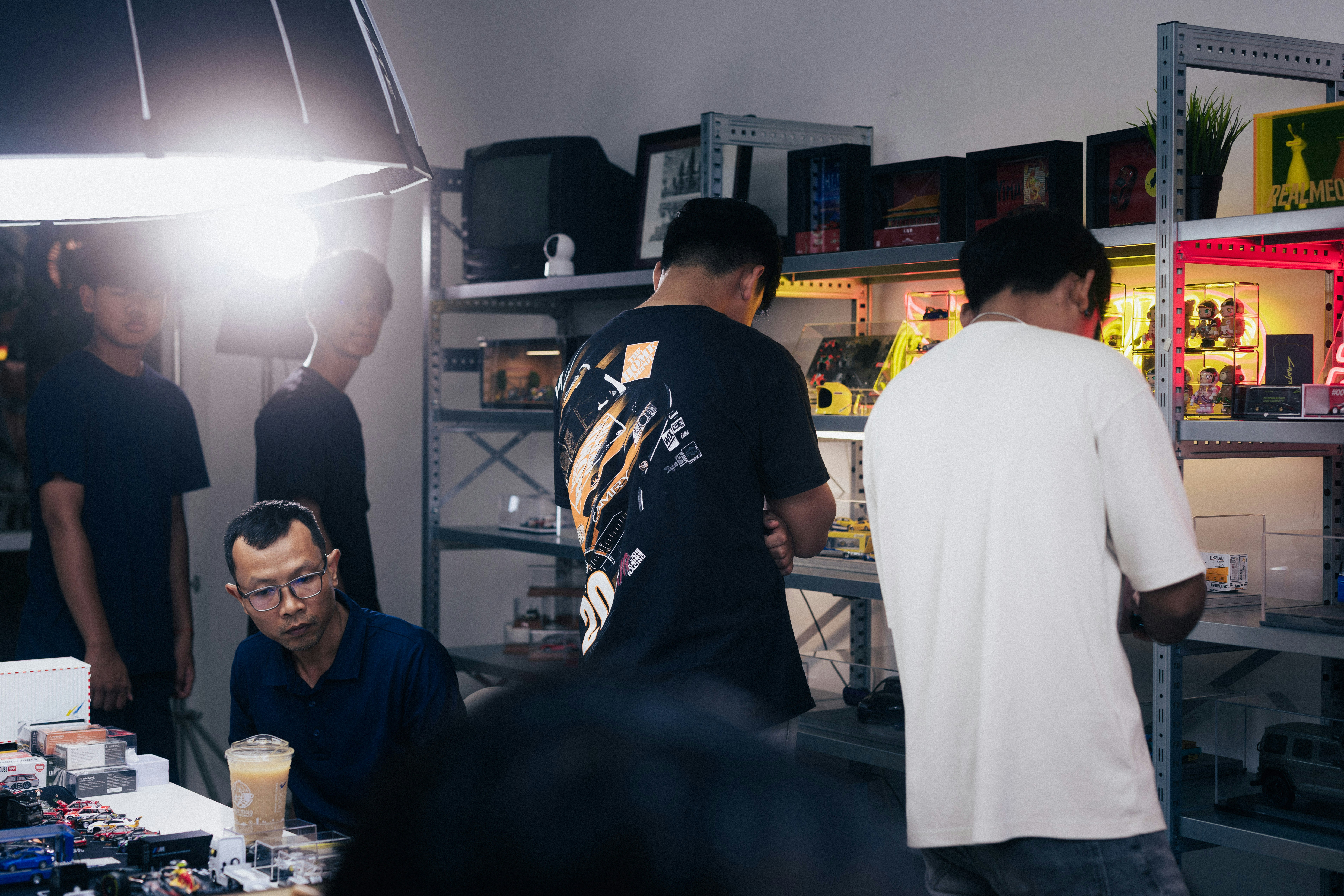 Individuals exploring a vibrant collection of items in a cozy shop, illuminated by soft lighting. The scene captures the essence of community and shared interests.