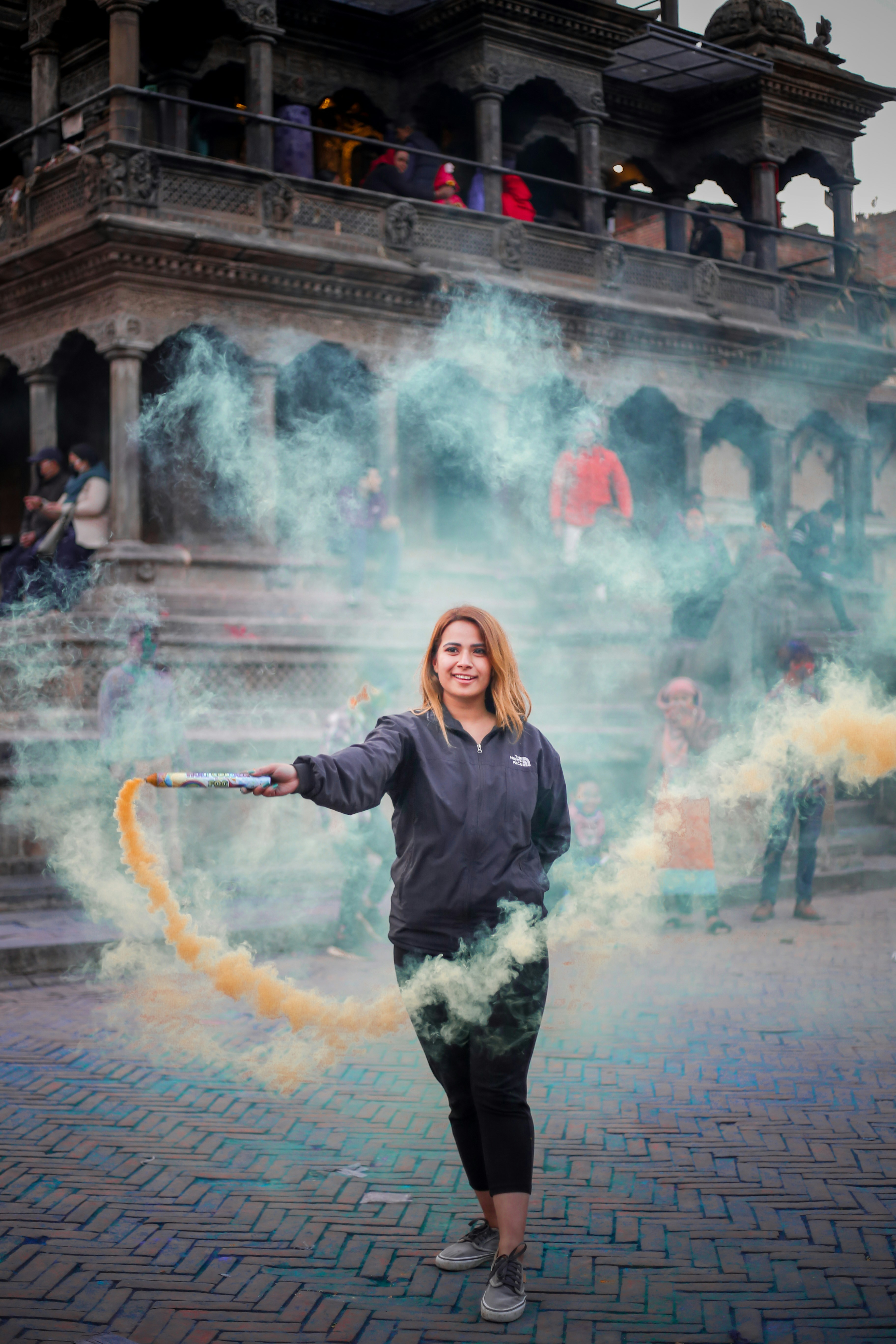 Spirals of Joy in the Ancient Courtyard | Woman holding smoke bombs with colorful smoke.