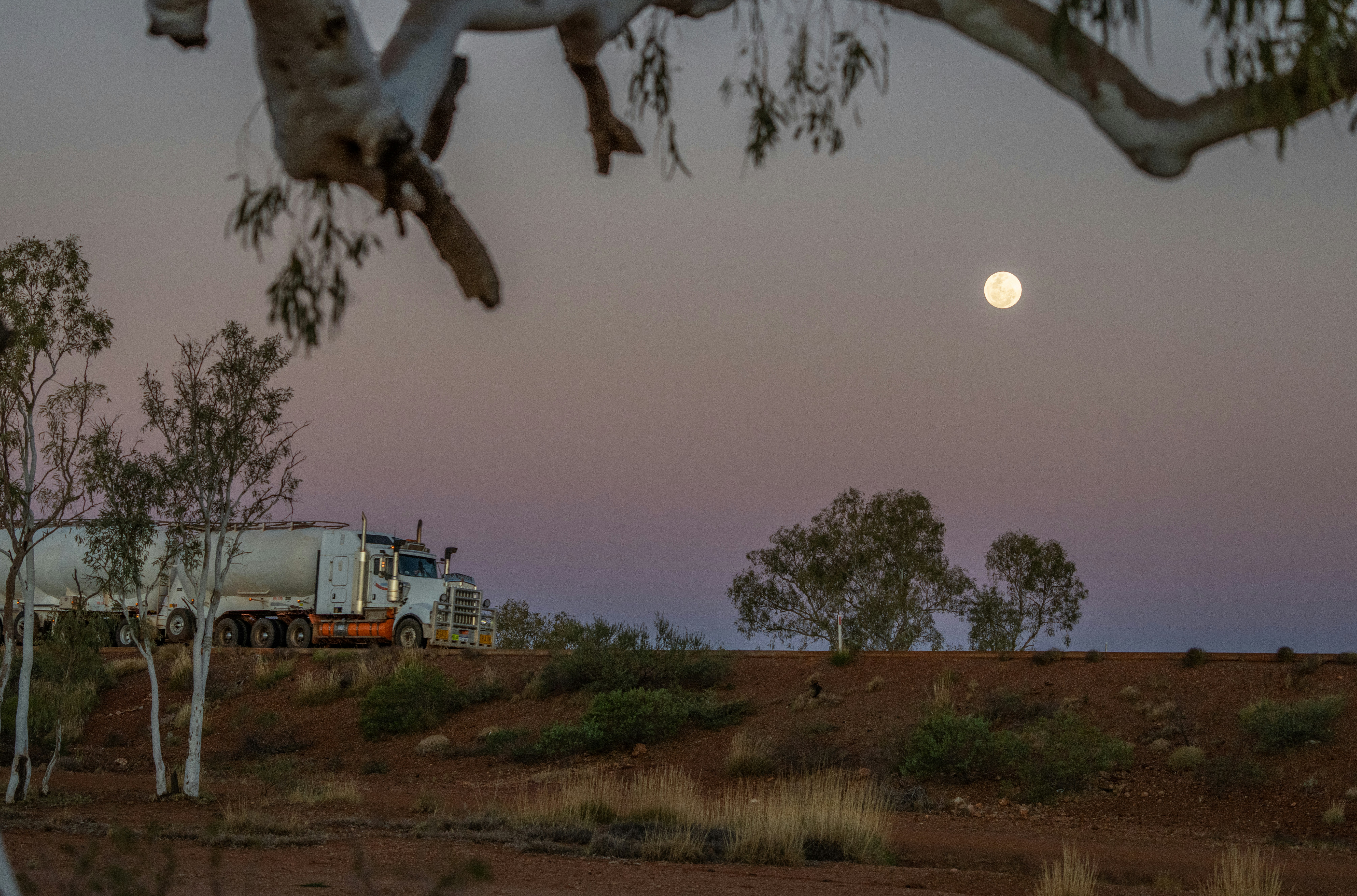 Full moon in a dusky sky over arid landscape
