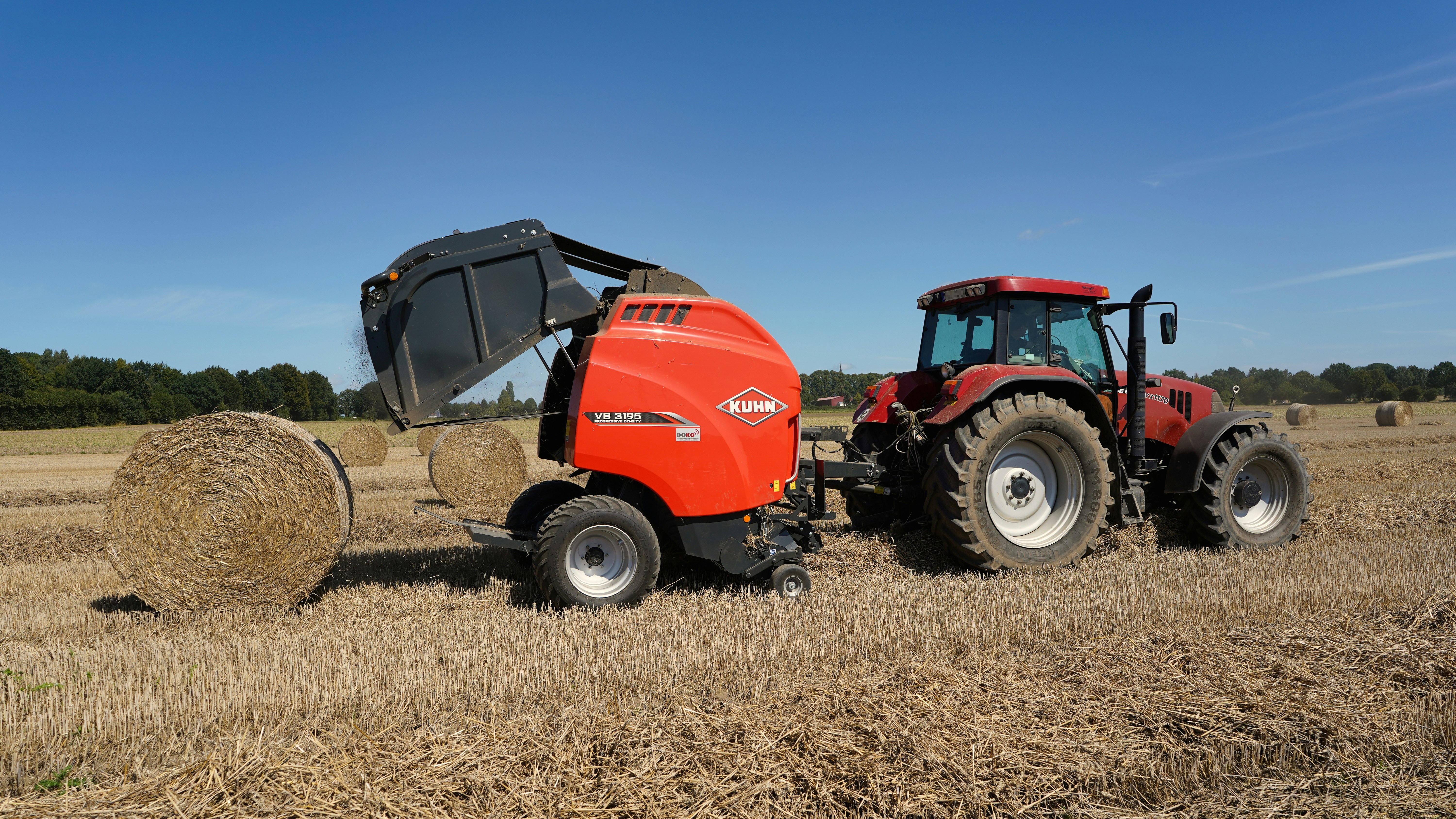 Red tractor pulling a round baler in a field photo – Free Deutschland ...