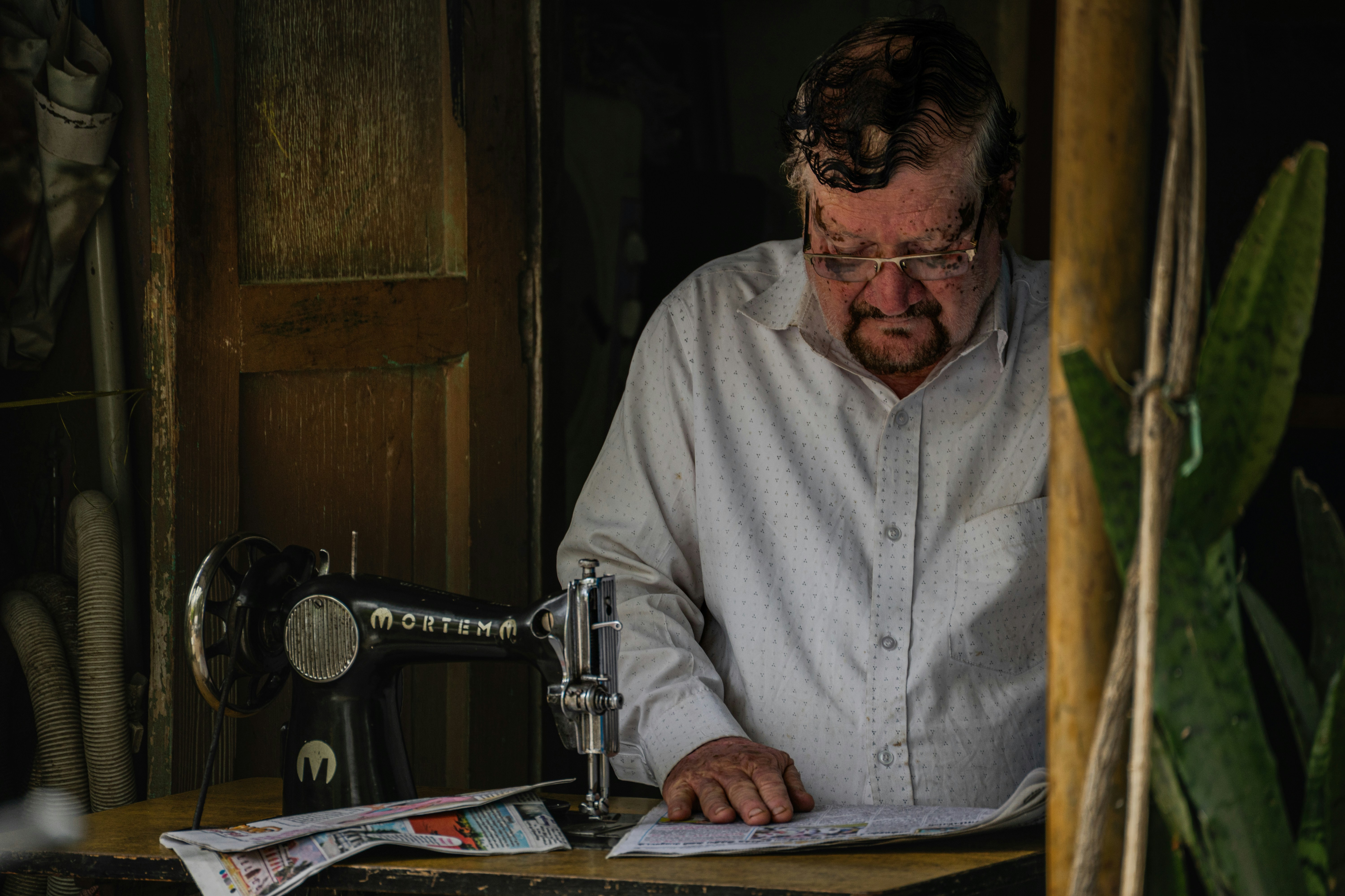 Skilled Tailor at Work: Senior Craftsman Sewing with Vintage Machine | Artisan Photography #Tailor #ArtisanLife #VintageSewing #CraftsmanSkills | Man in white shirt sewing with vintage machine