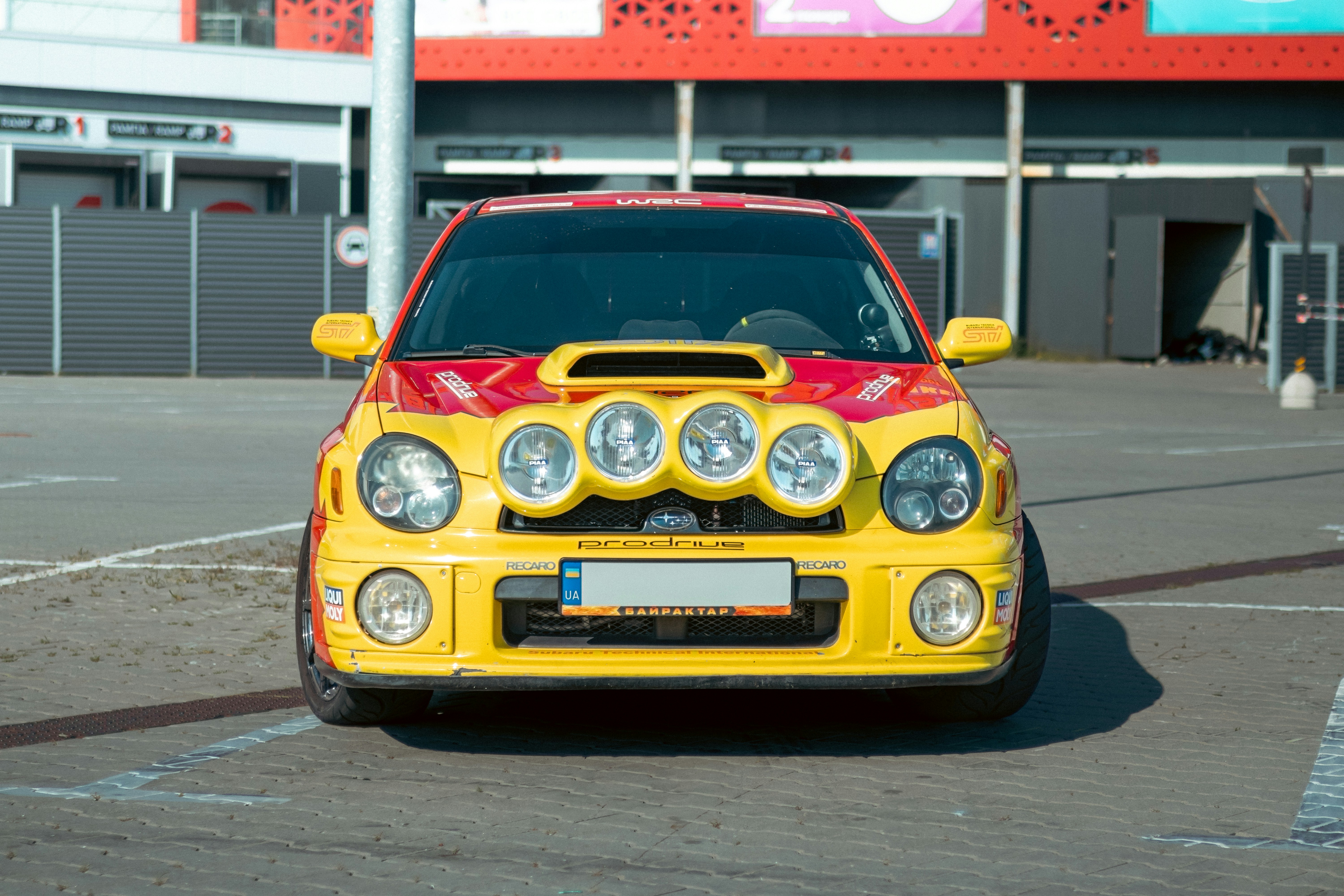 Bright yellow rally car with multiple headlights parked in an urban setting. The design showcases a unique blend of performance and style.