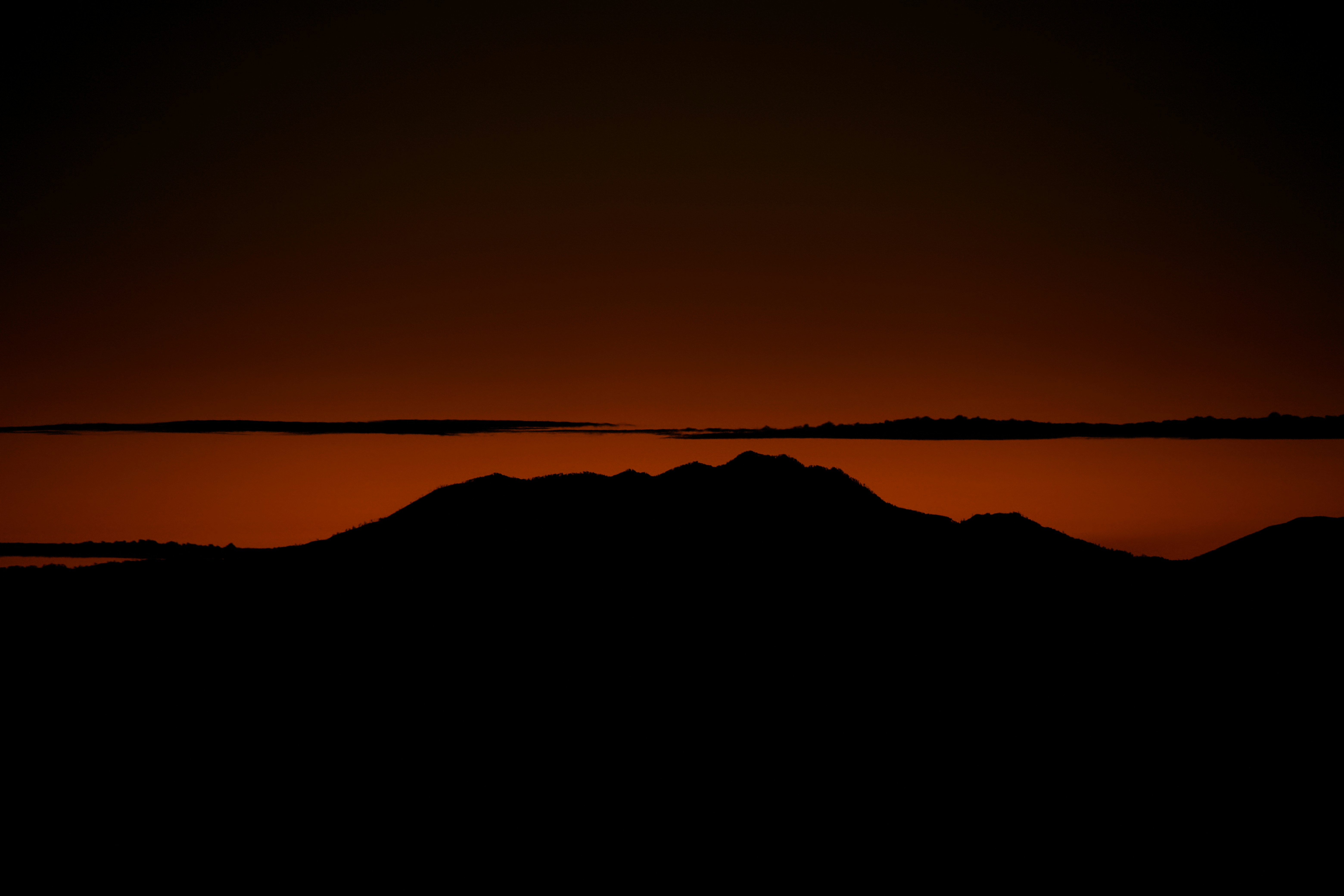 Dark silhouette of mountains against a red sunset
