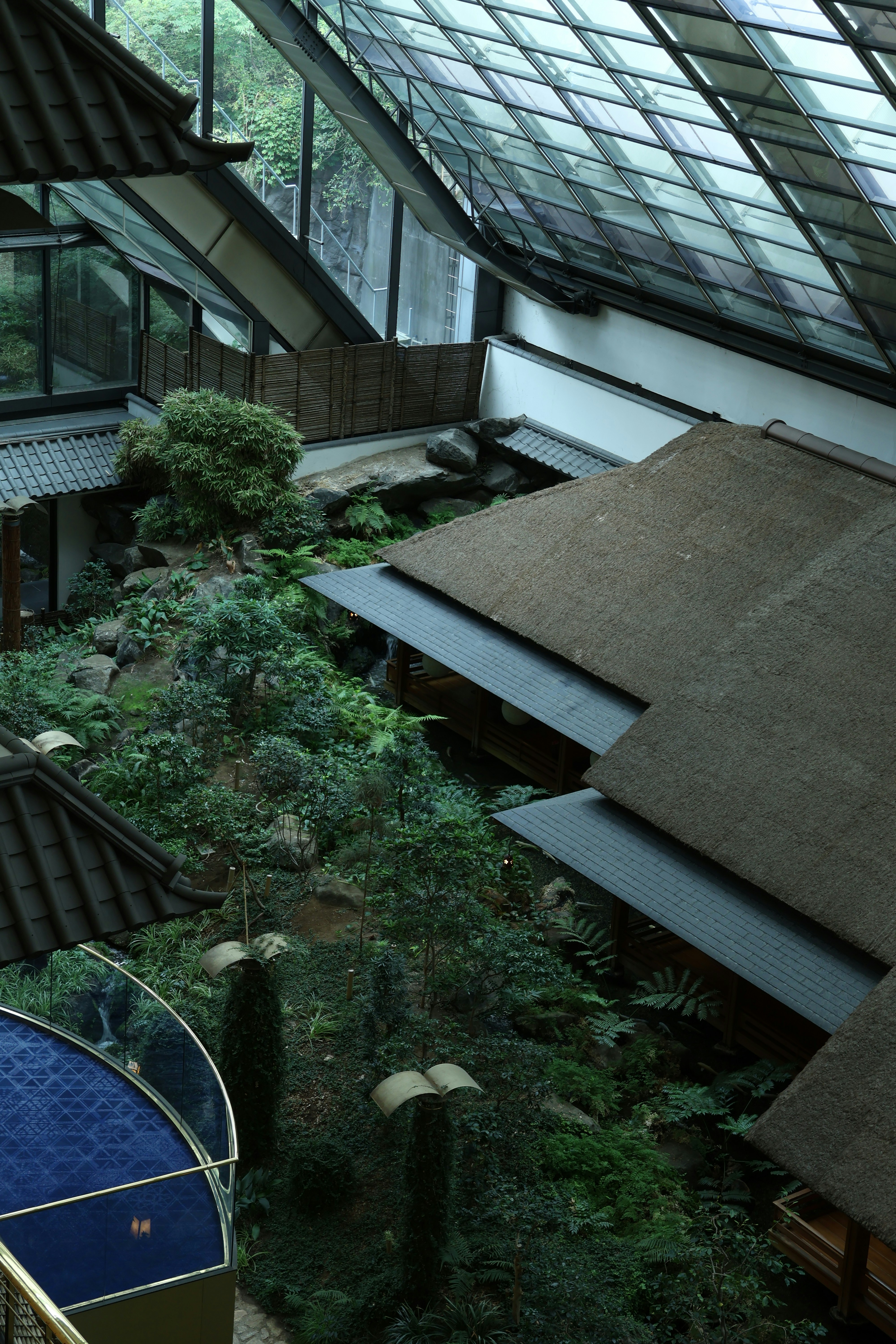 Hotel Gajoen has a garden that extends from the entrance to the other end of the hotel. | Modern atrium with lush greenery and glass ceiling