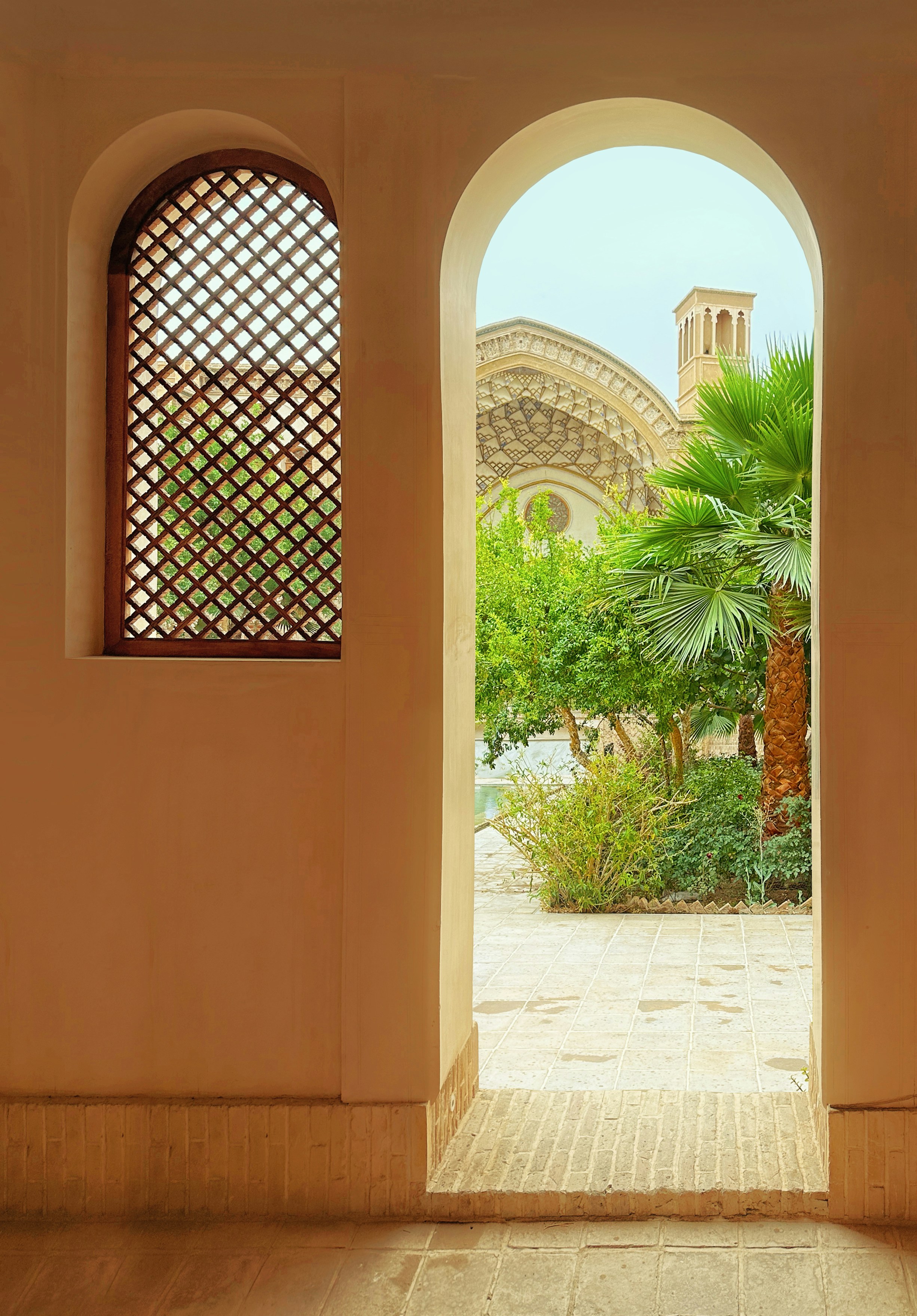 Arched doorway revealing a courtyard with greenery and building
