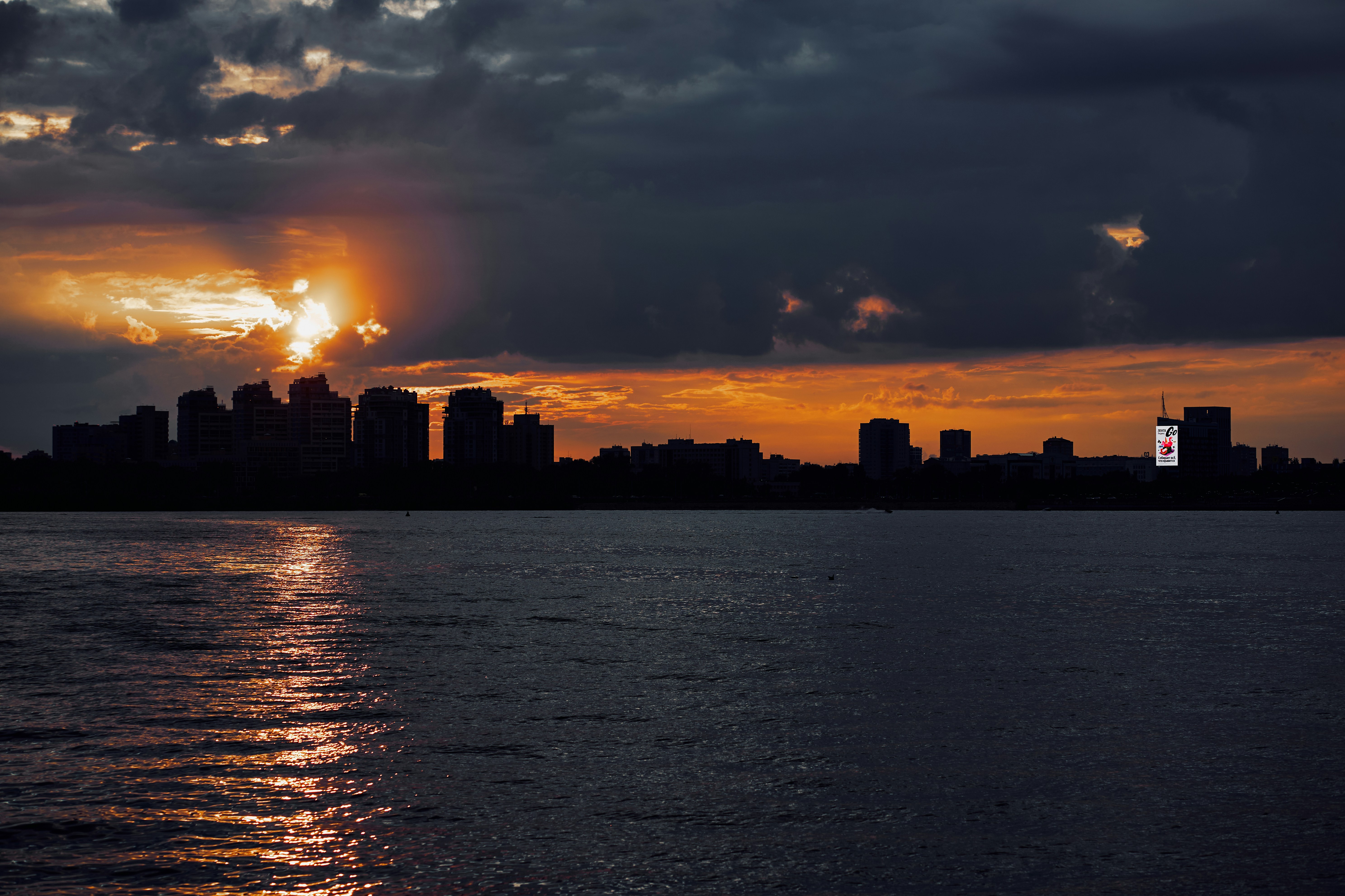 Dramatic sunset over a city skyline and water.