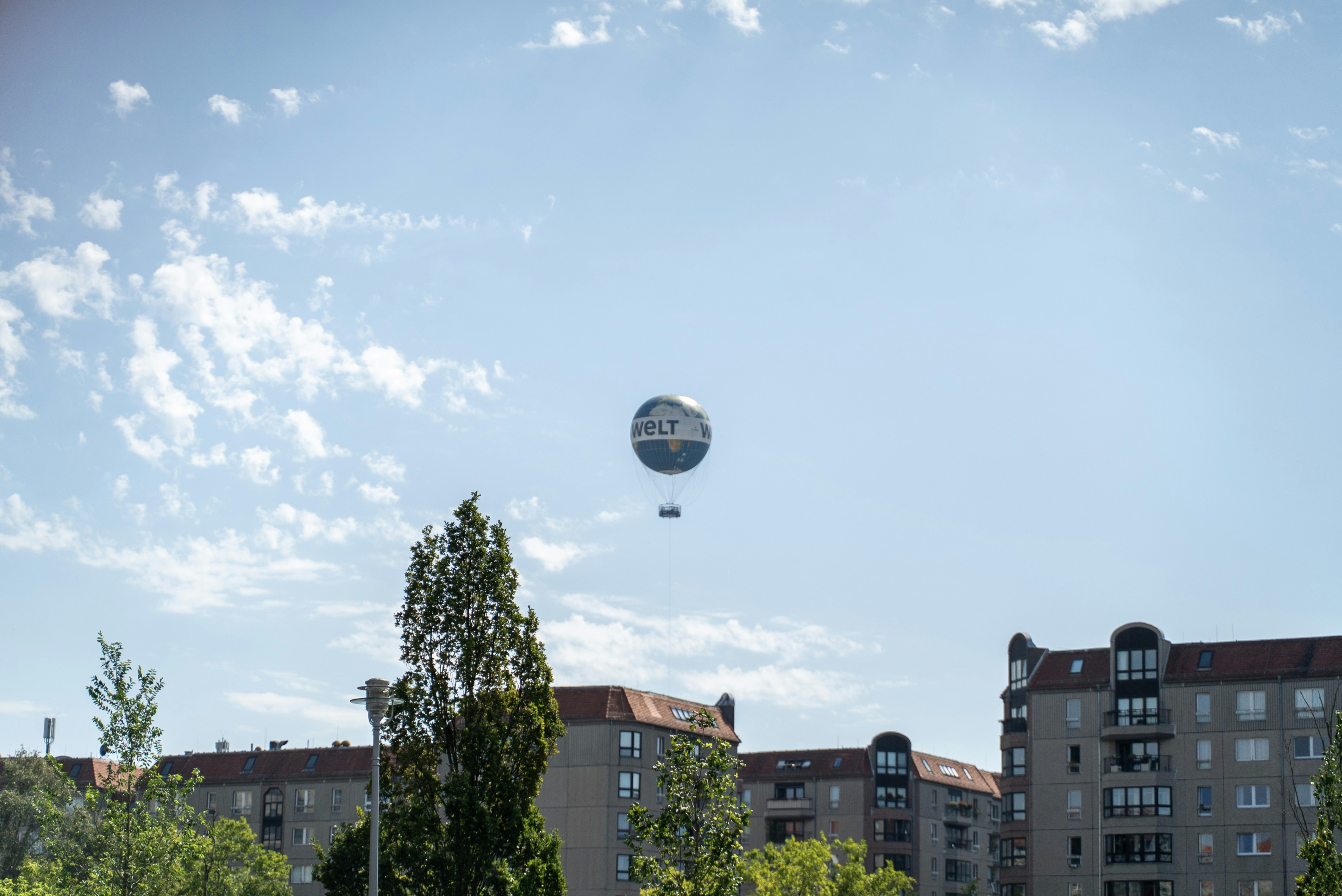 Hot air balloon floats in the sky above buildings