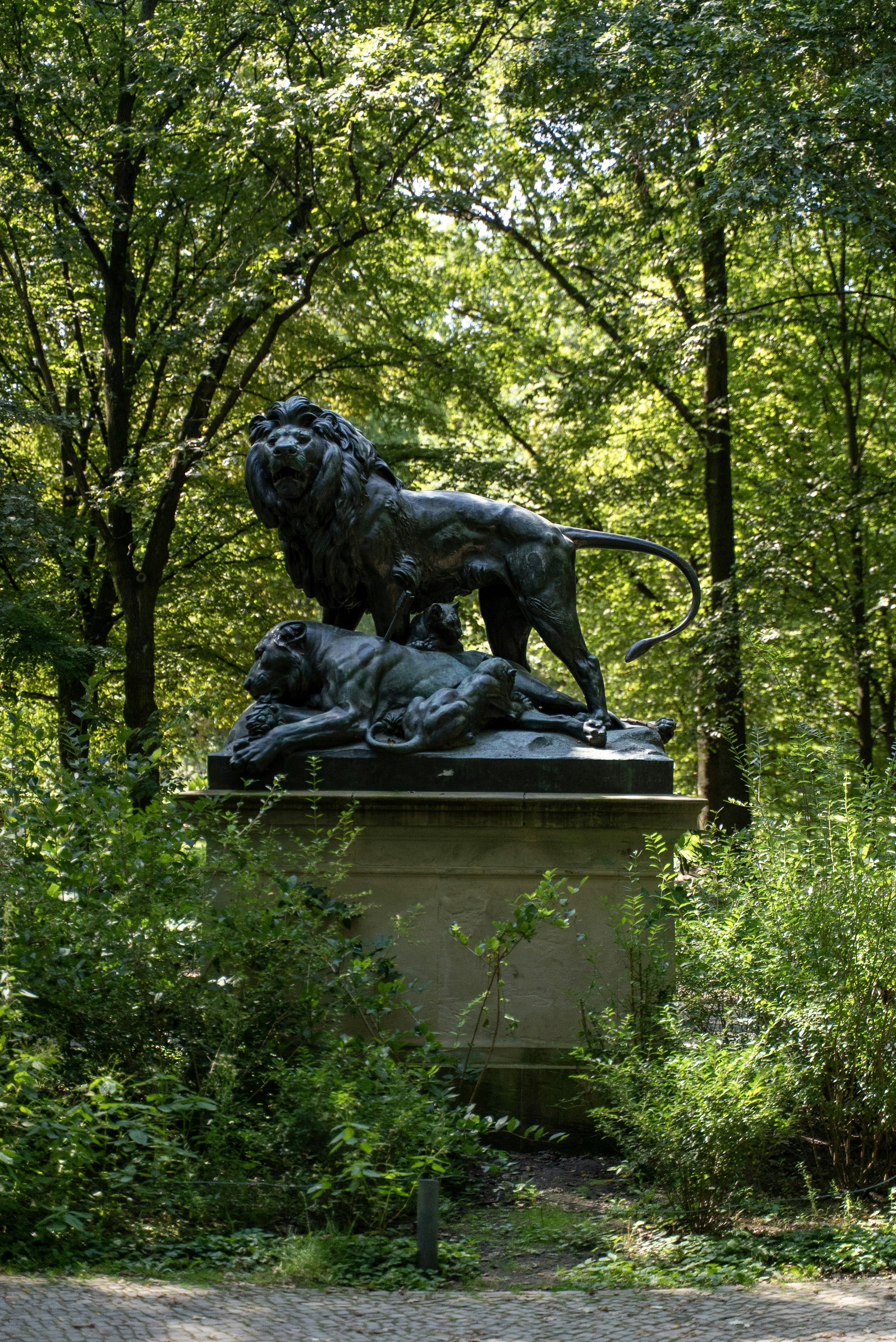 Bronze lion sculpture in a lush green forest setting