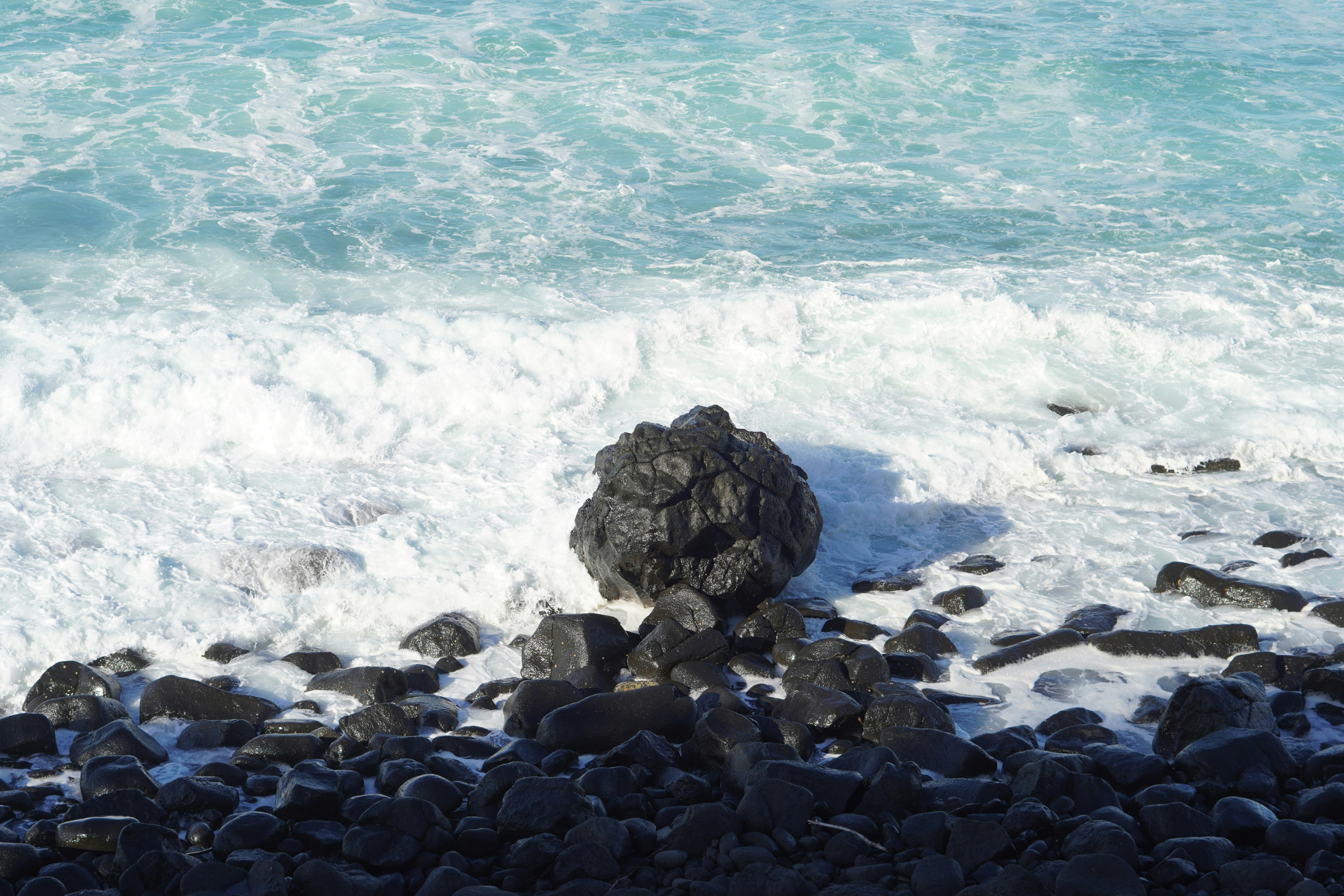 Black rocks on a beach with crashing waves