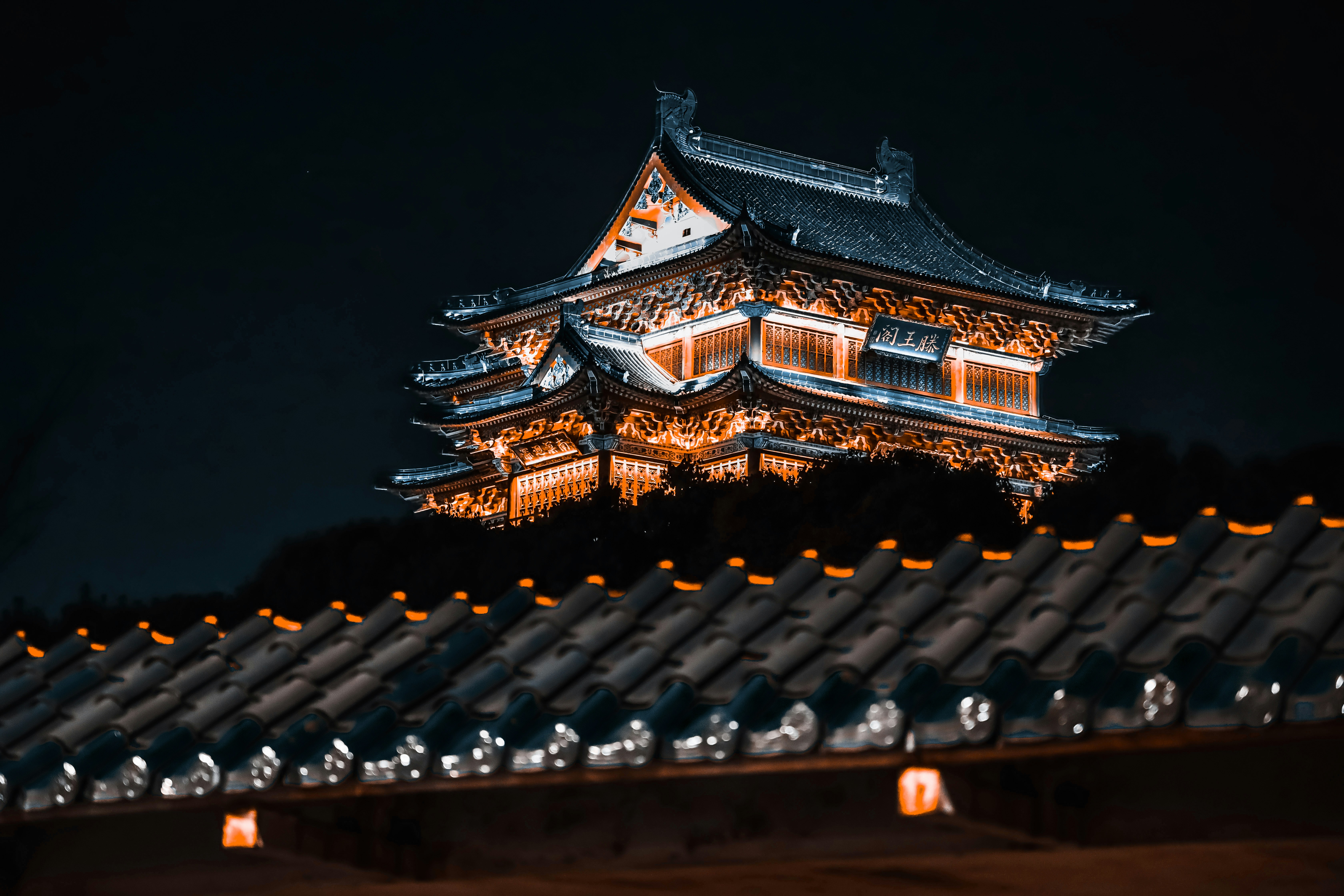 A serene night view of traditional Chinese architecture, glowing warmly under the night sky, showcasing the timeless elegance of ancient design. | Illuminated traditional japanese building at night