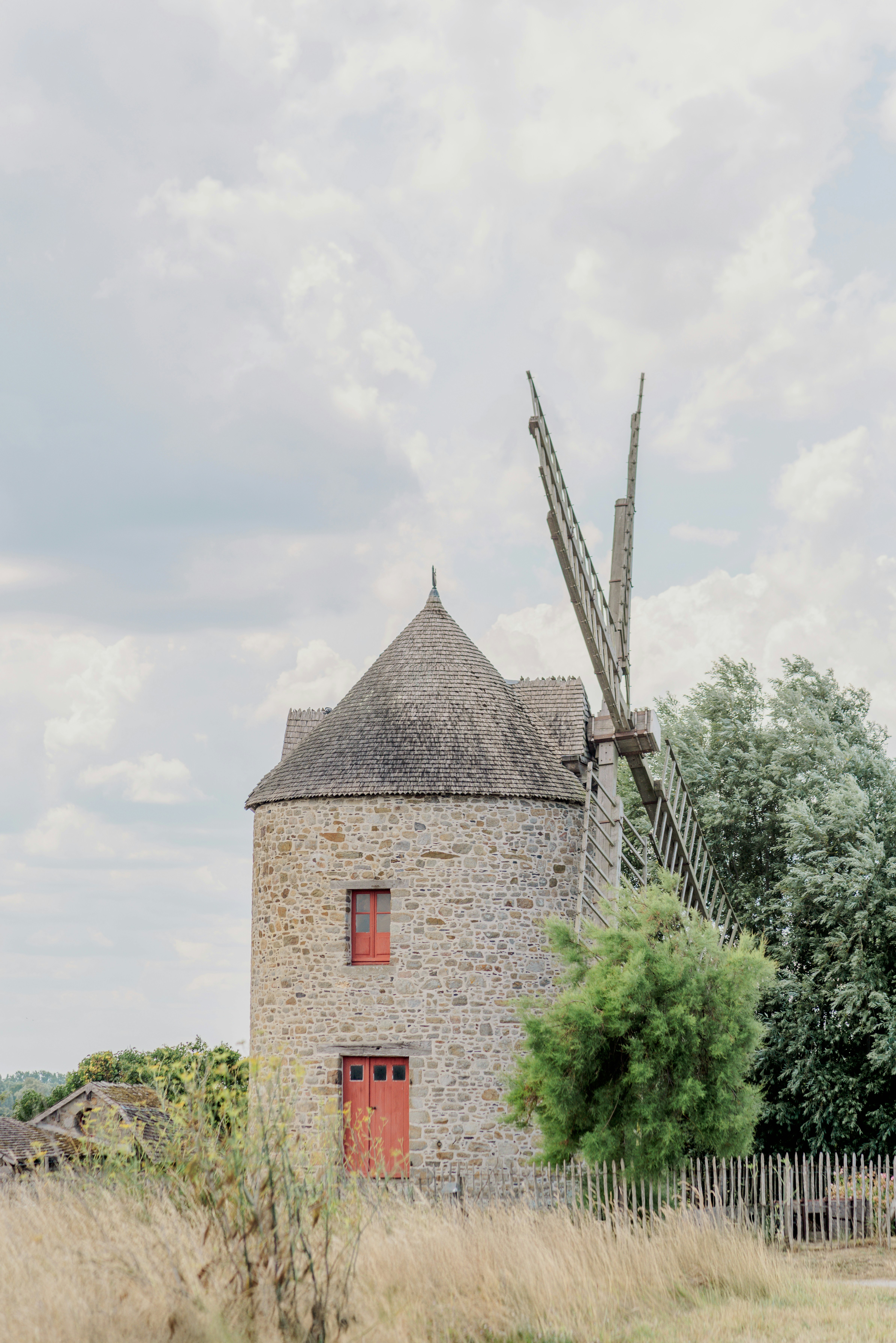 Stone windmill with red doors under cloudy sky