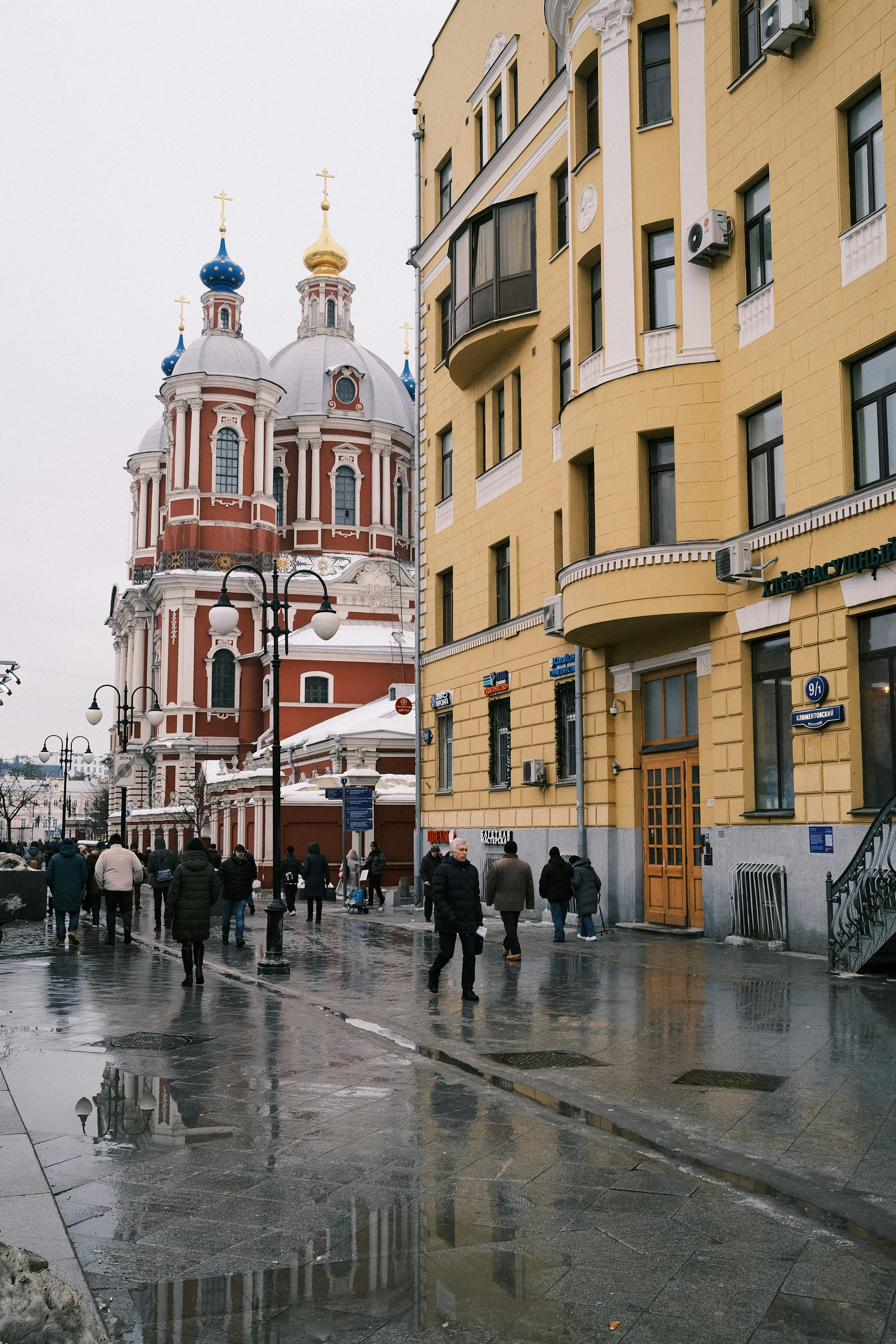 Wet city street with people and church