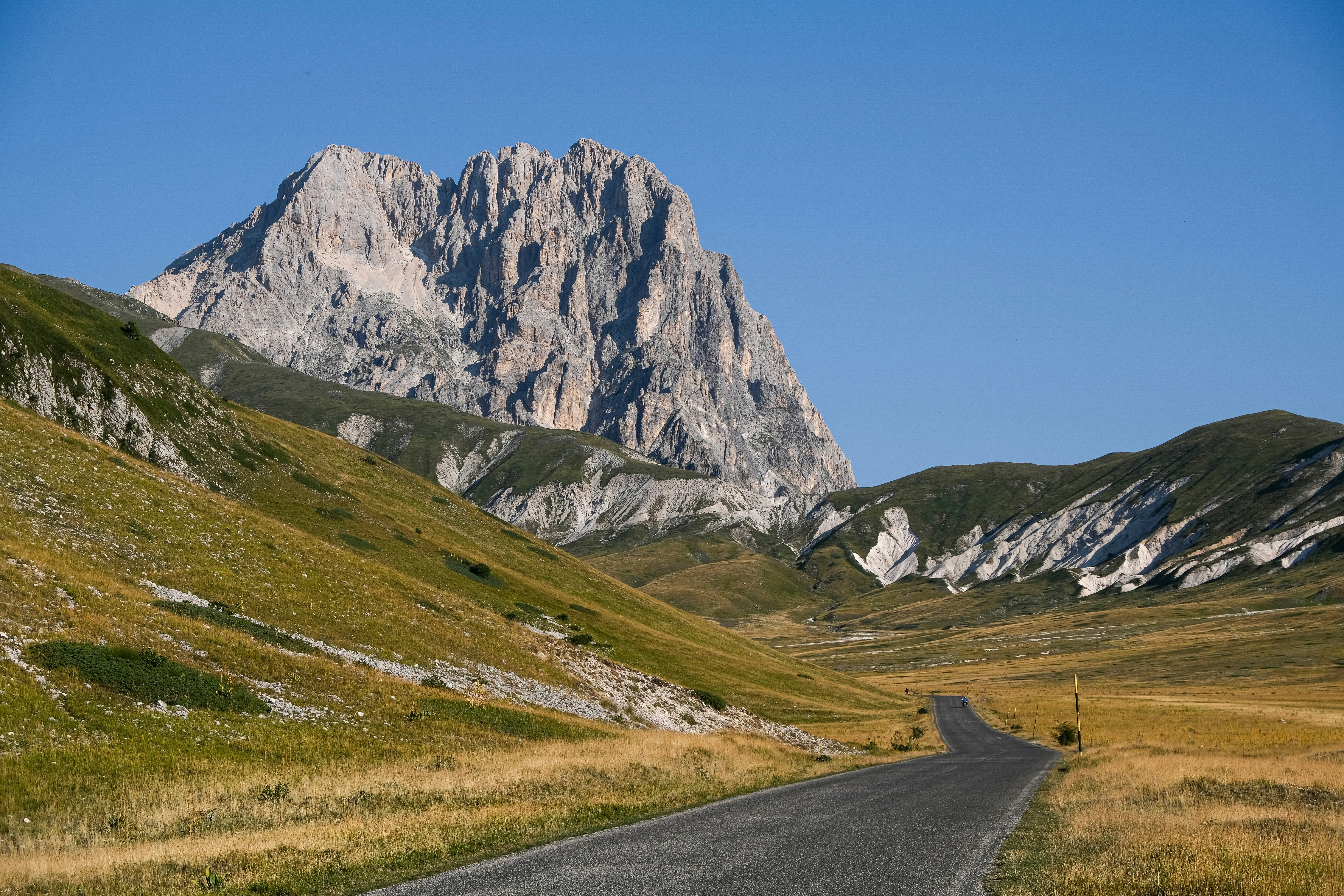 Majestic mountain towering over a winding road in a serene landscape, showcasing the harmony between nature and human pathways.