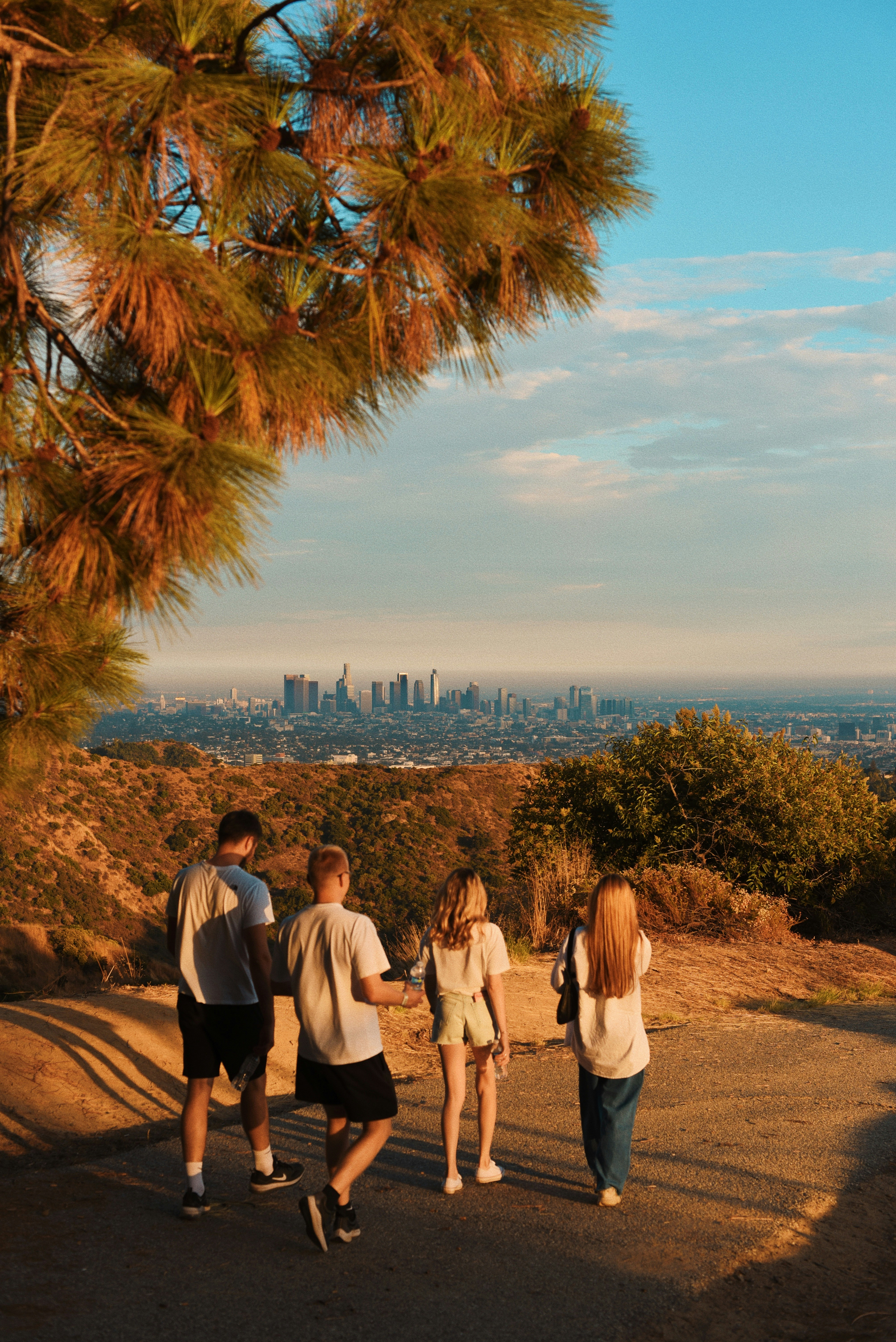 Friends and the Skyline | Four friends walk towards a city skyline at sunset