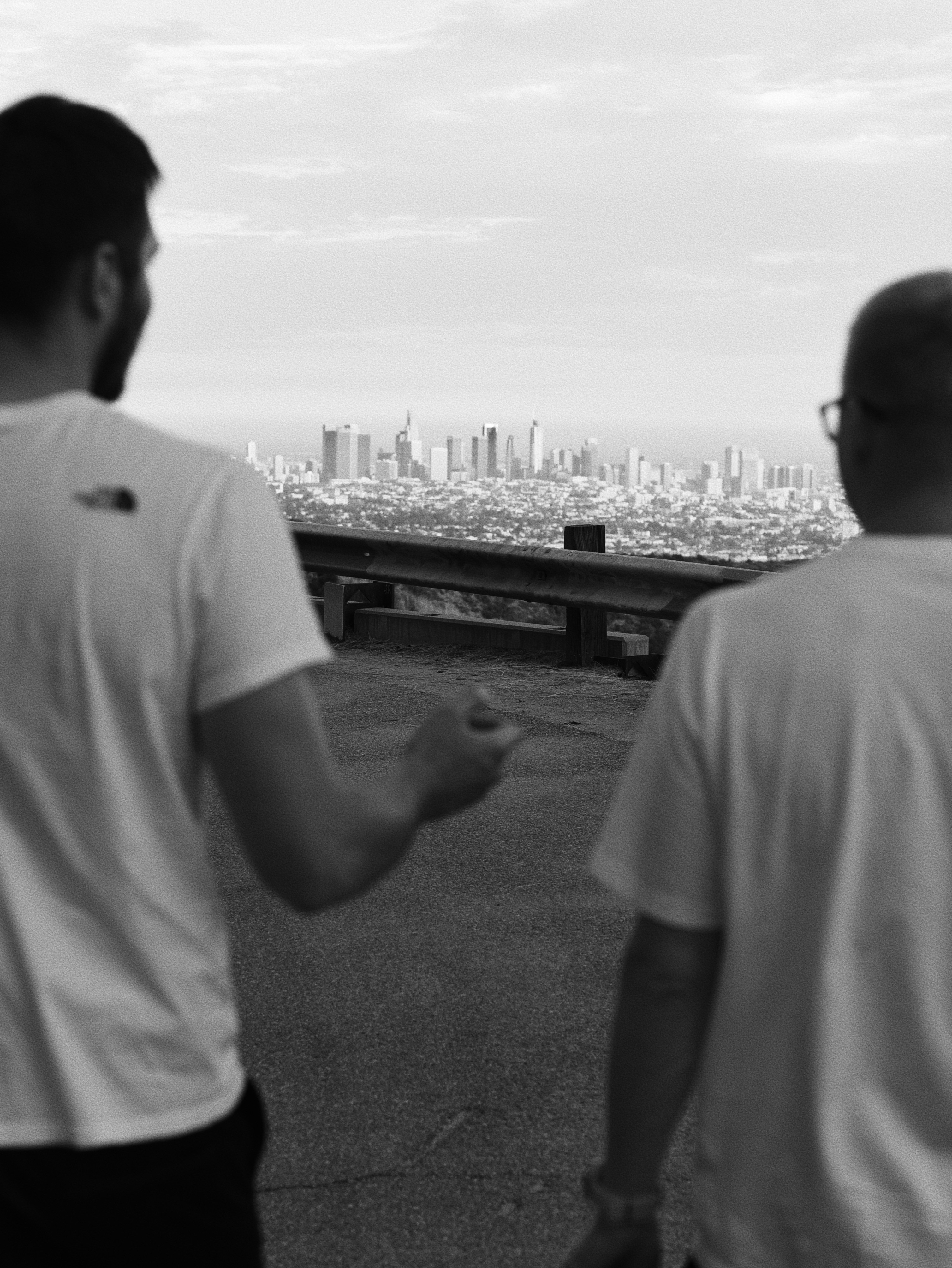 Two individuals converse while overlooking a sprawling cityscape, capturing a moment of connection against an urban backdrop.