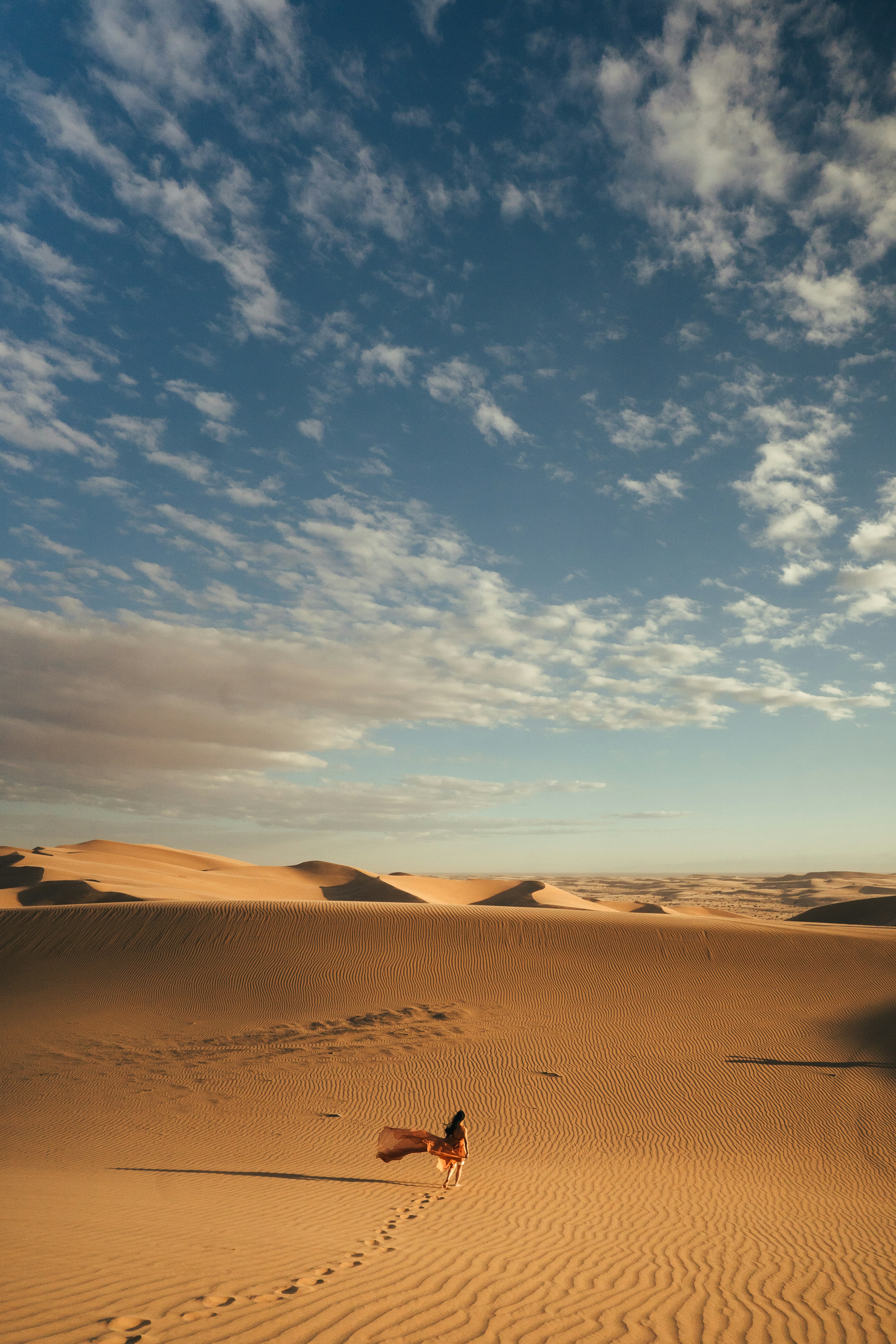 Photoshoot at the Imperial Sand Dunes | Woman in flowing dress walking across sand dunes.