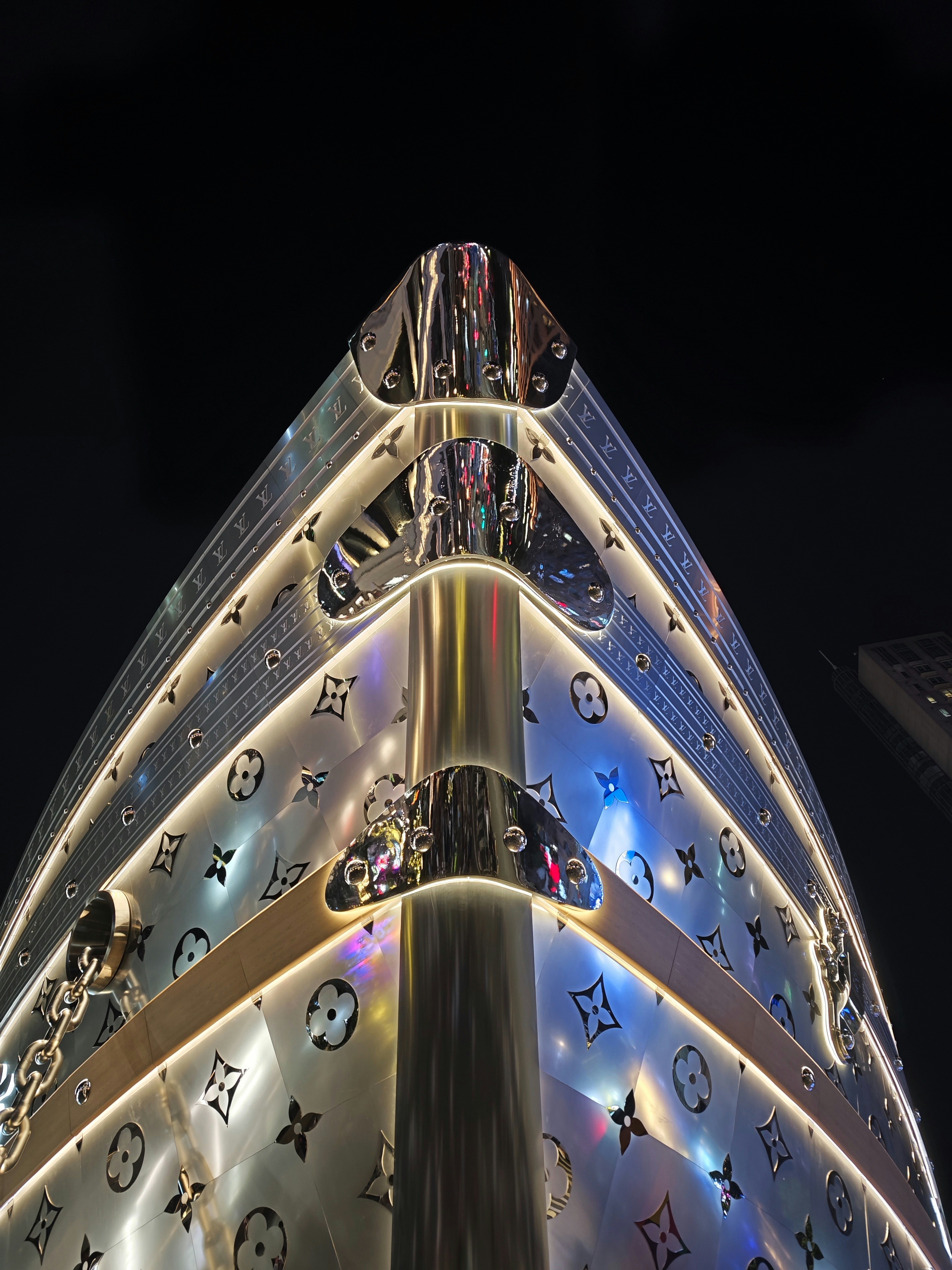 Louis Vuitton | Modern building illuminated at night with reflective surfaces.
