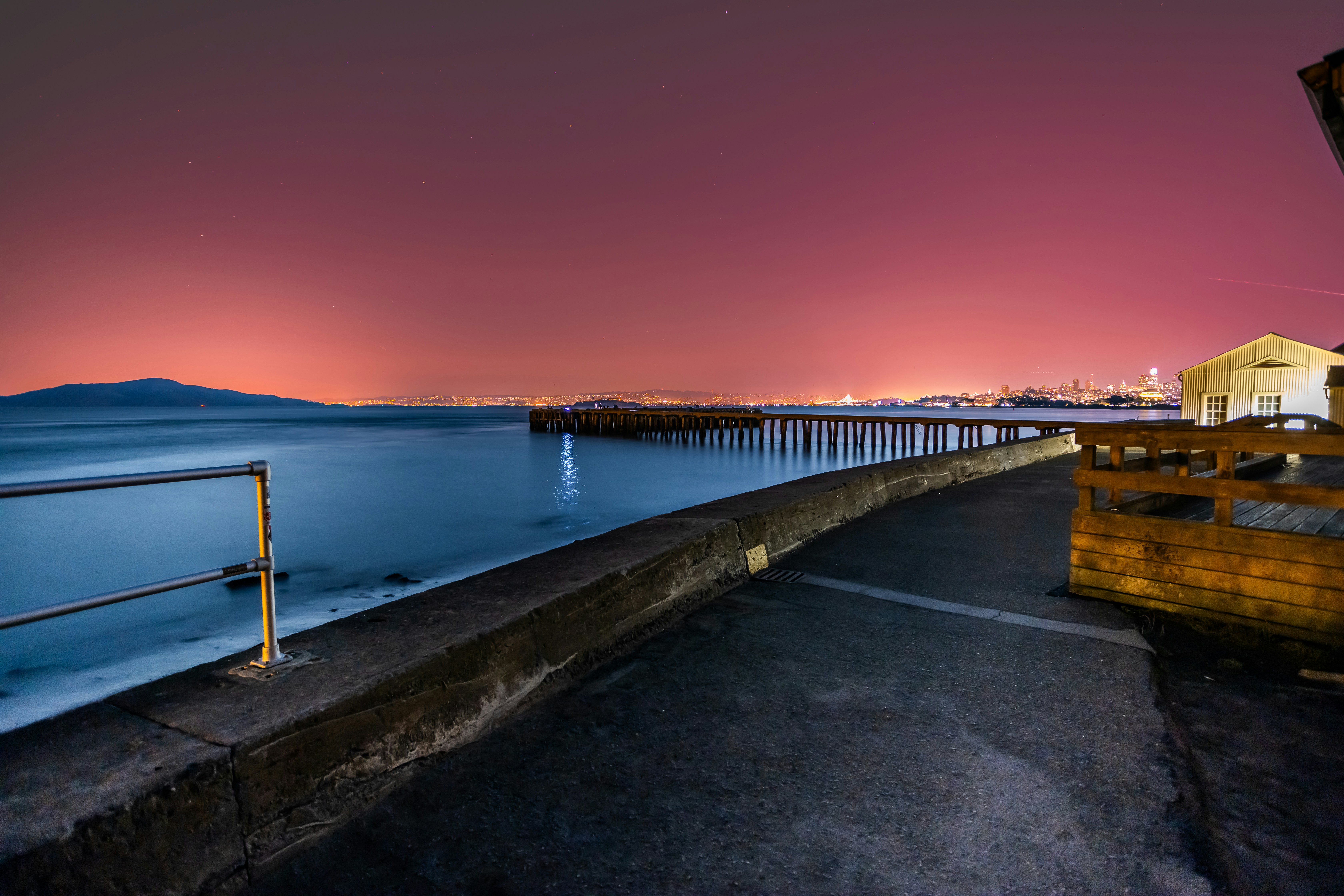 Nighttime waterfront with glowing sky and city lights