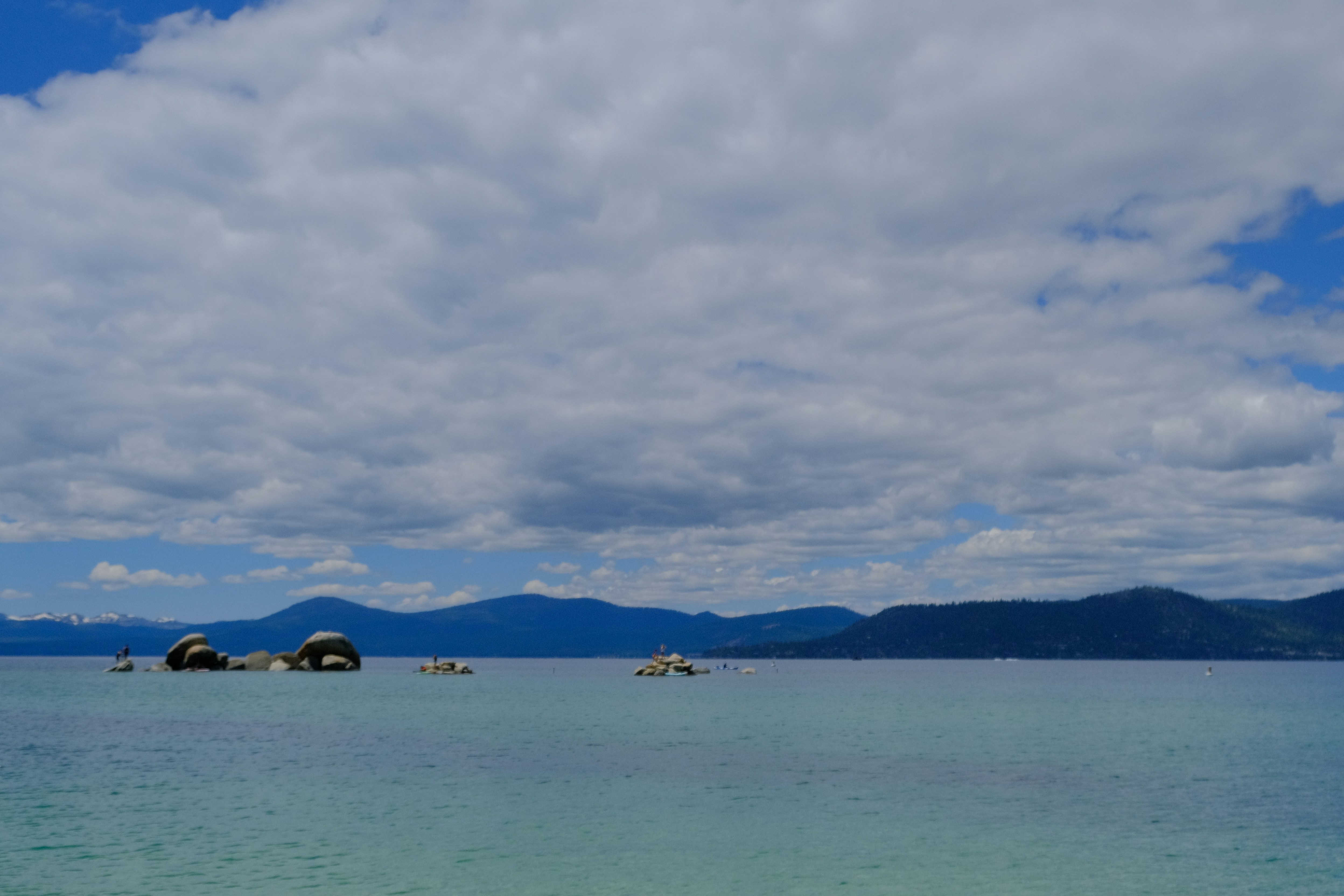 Calm waters reflecting a dramatic sky, with rocky formations emerging from the lake's surface. Scenic view captures the tranquility of nature.