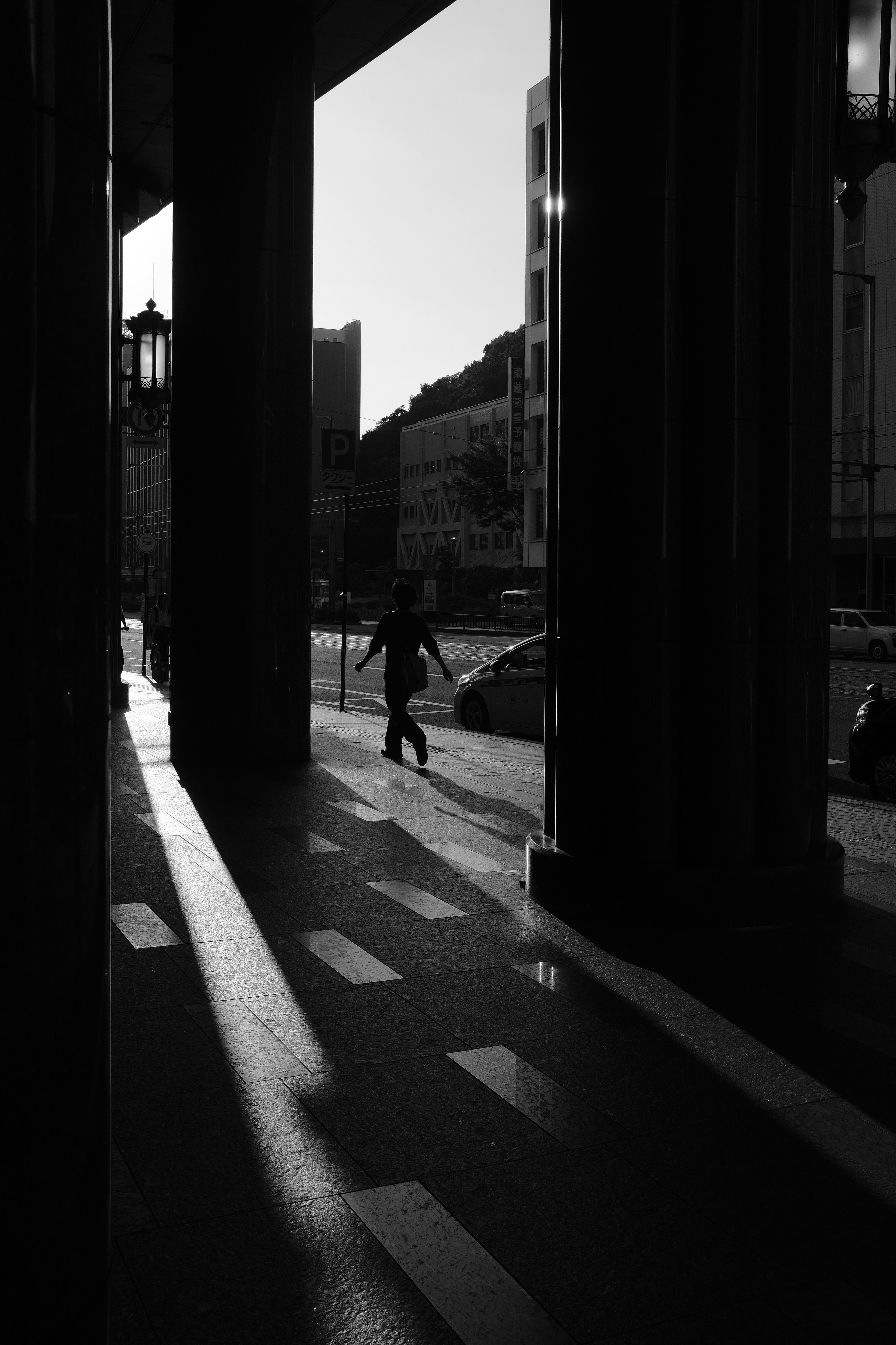 Silhouette of a person walking under arched colonnade