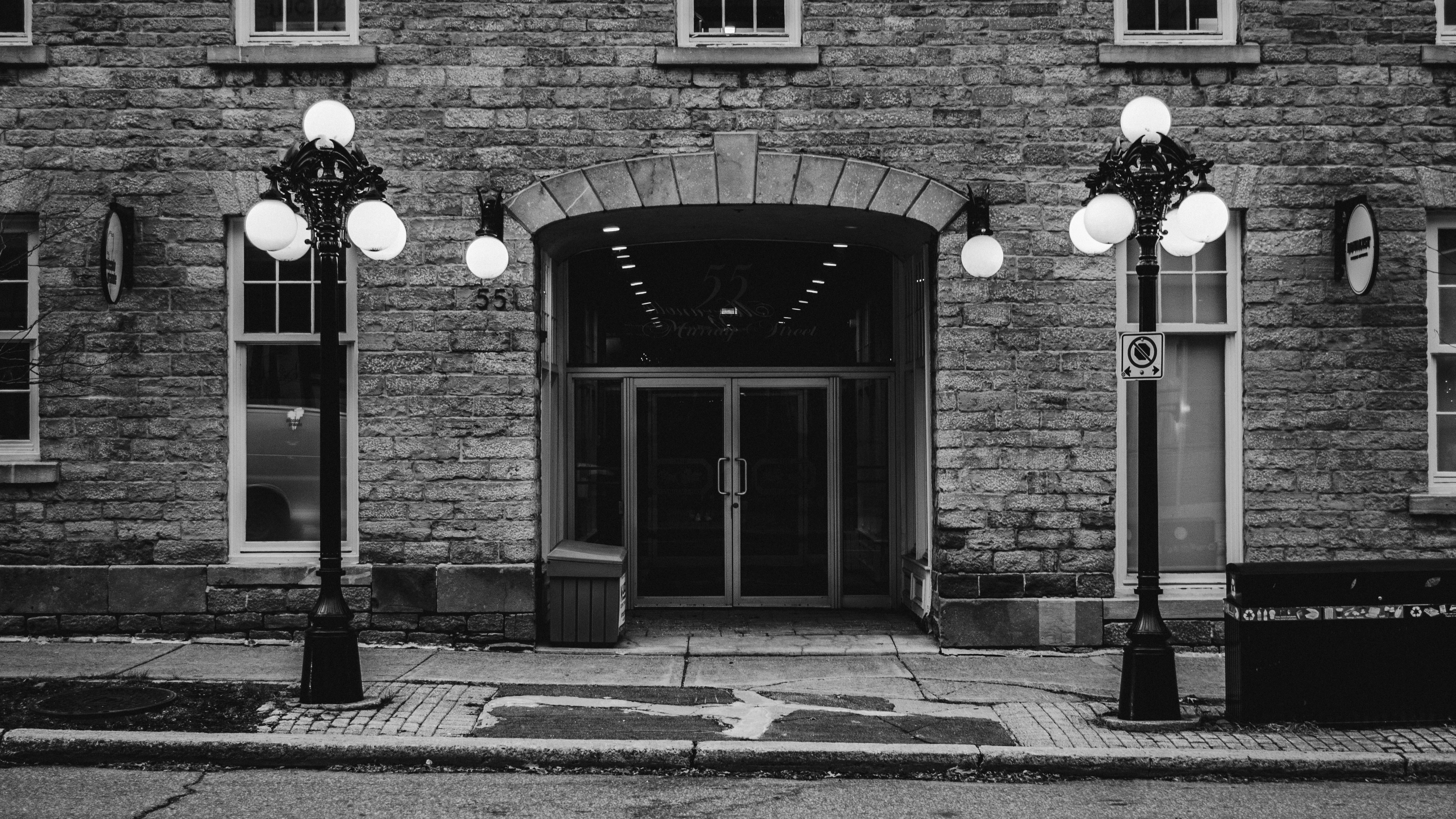 An inviting urban entrance framed by vintage street lamps, showcasing timeless architecture and street charm. | Entrance to a brick building with lamps