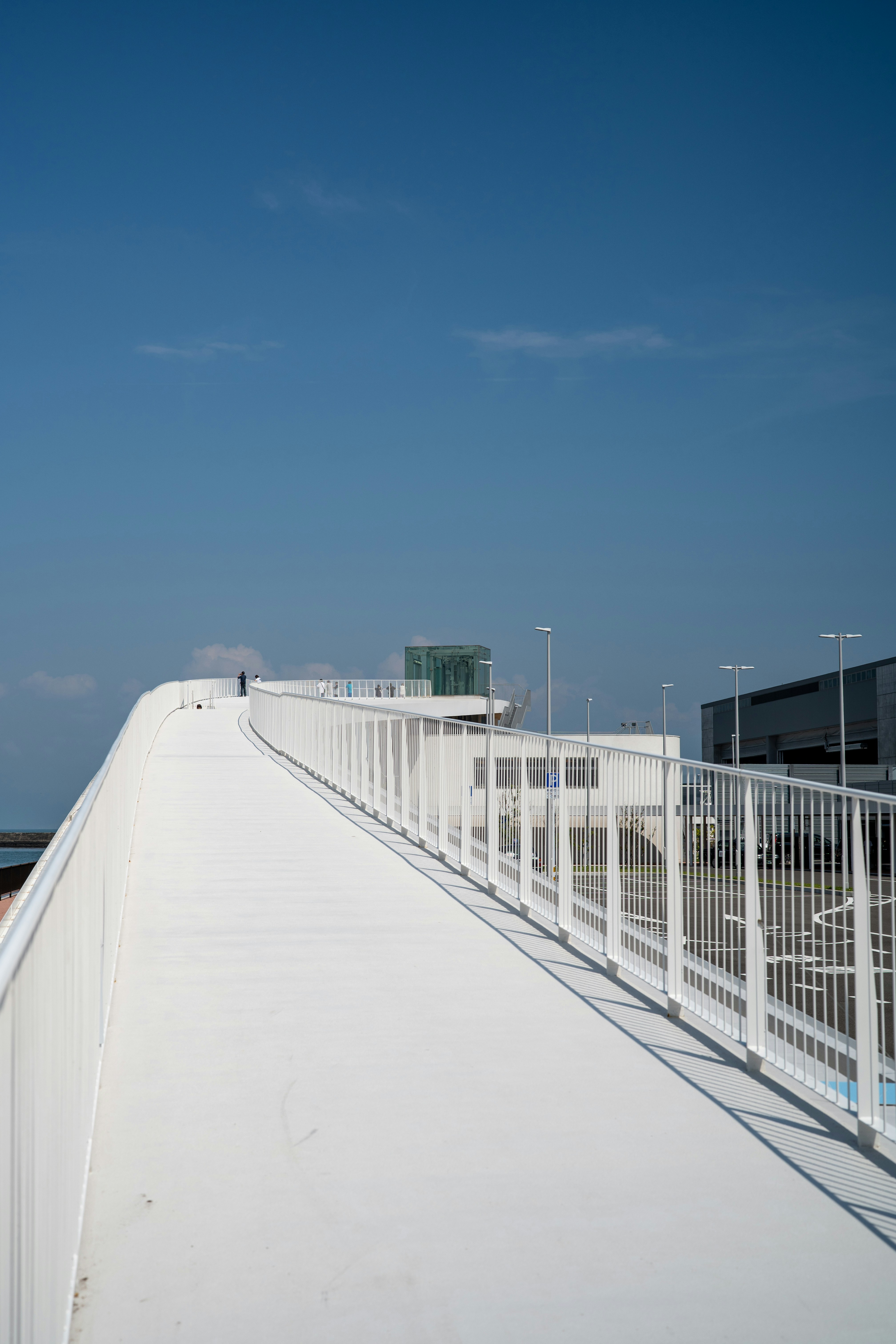 Modern white pedestrian bridge under a clear blue sky.