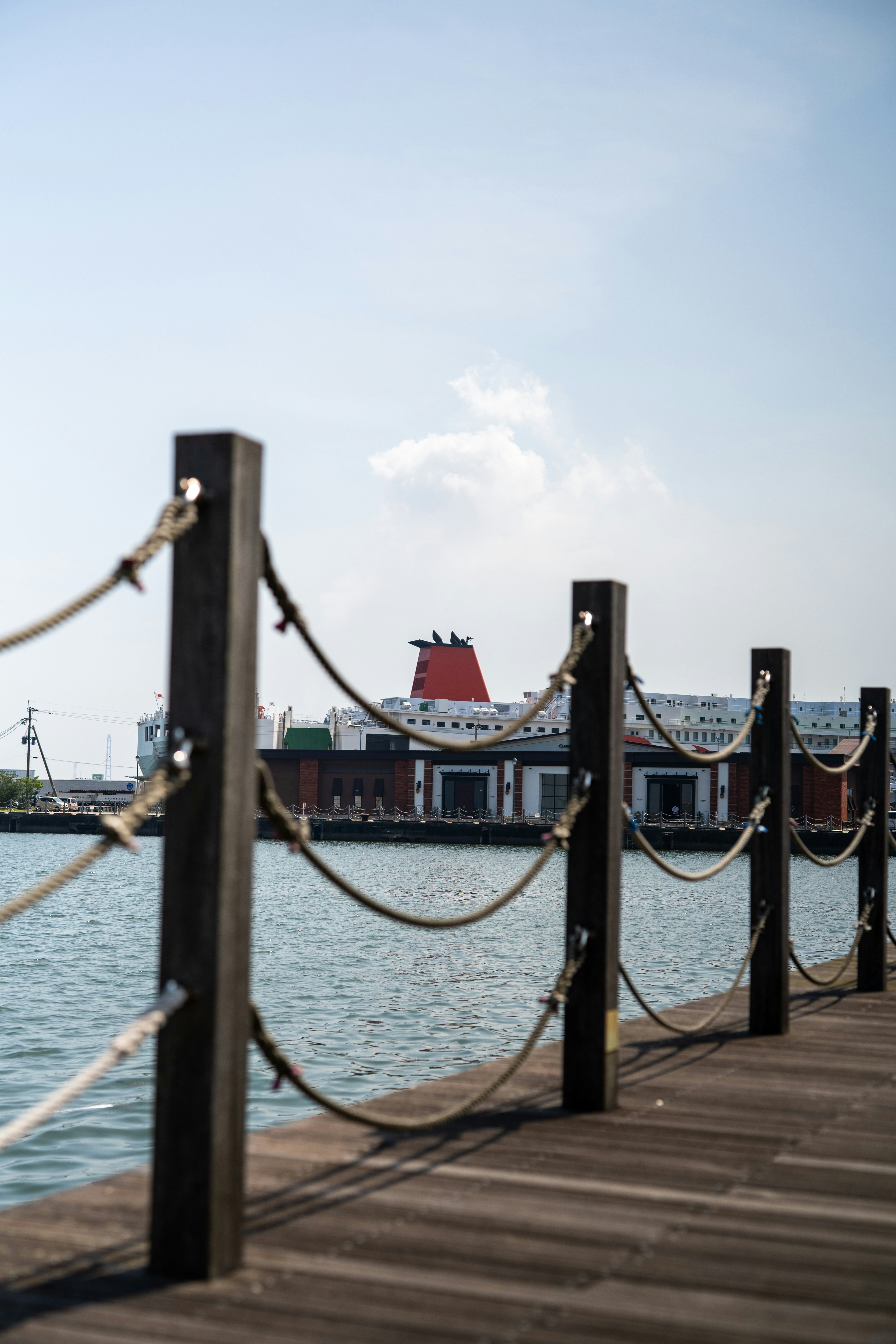 Wooden pier with rope railing and ferry in background