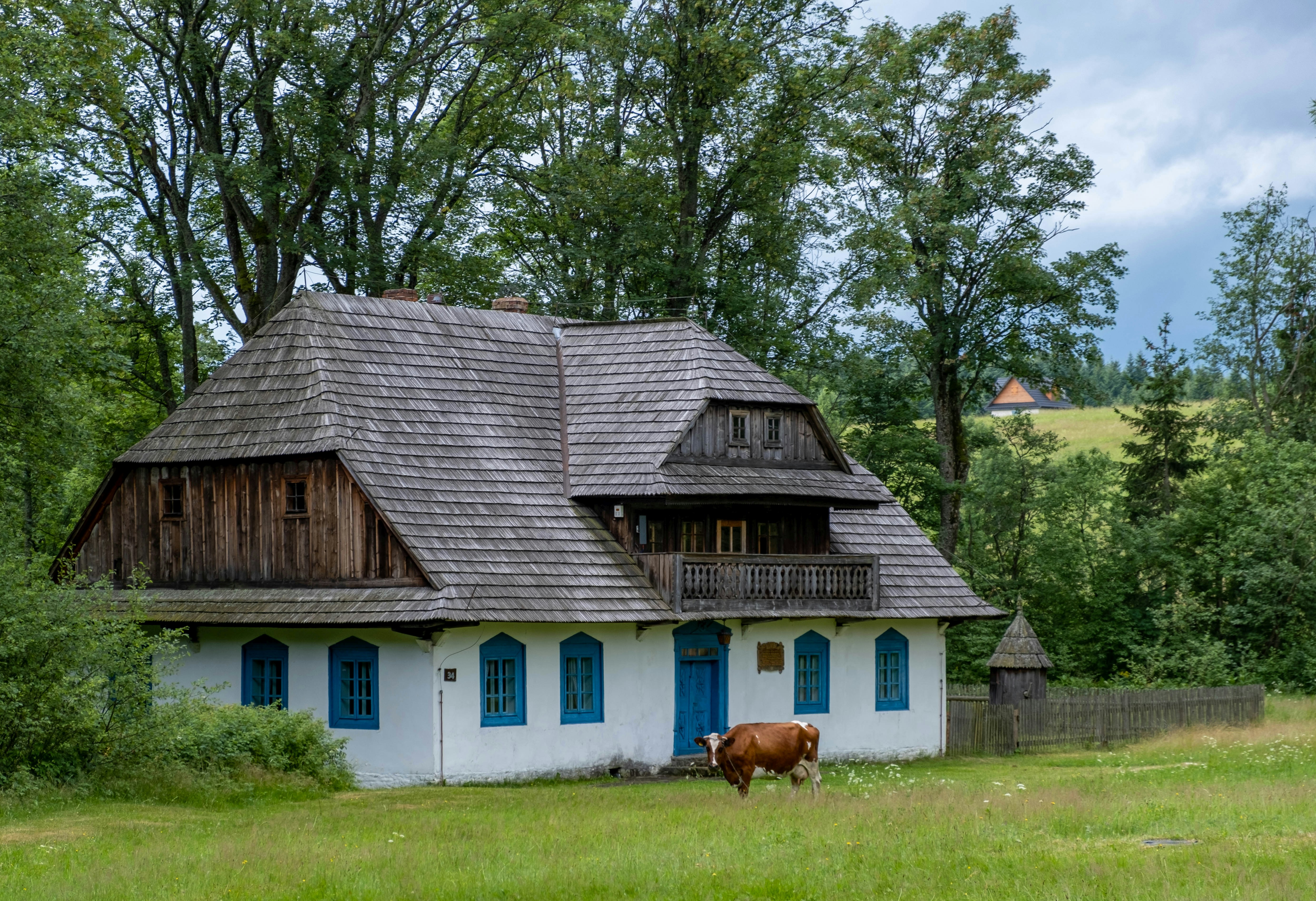 The Orava Ethnographic Park in Zubrzyca Górna, Poland. | Traditional wooden house with a gray roof surrounded by trees.