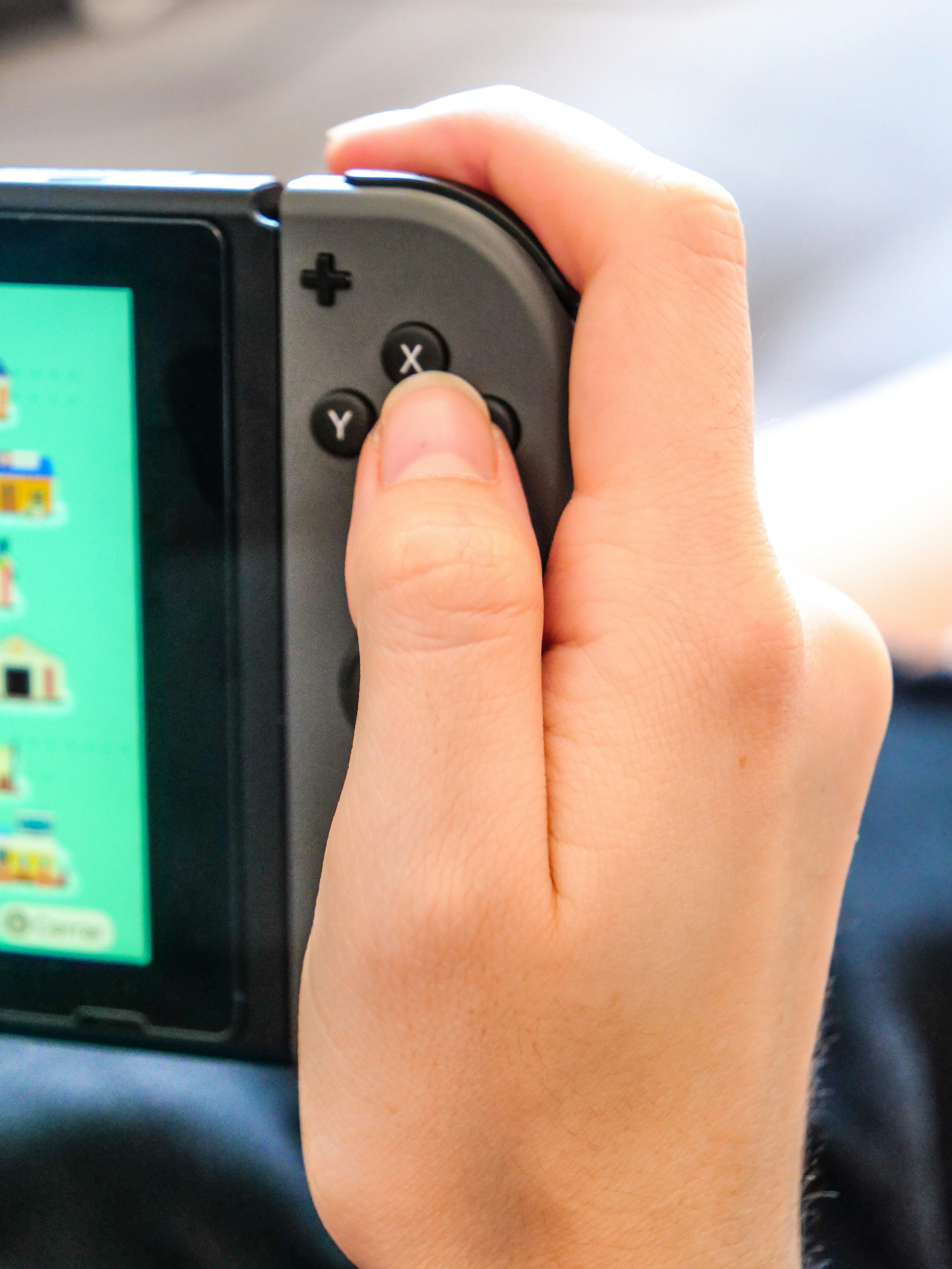 X Button in Focus: Close-Up of a Hand Gripping a Left Joy-Con