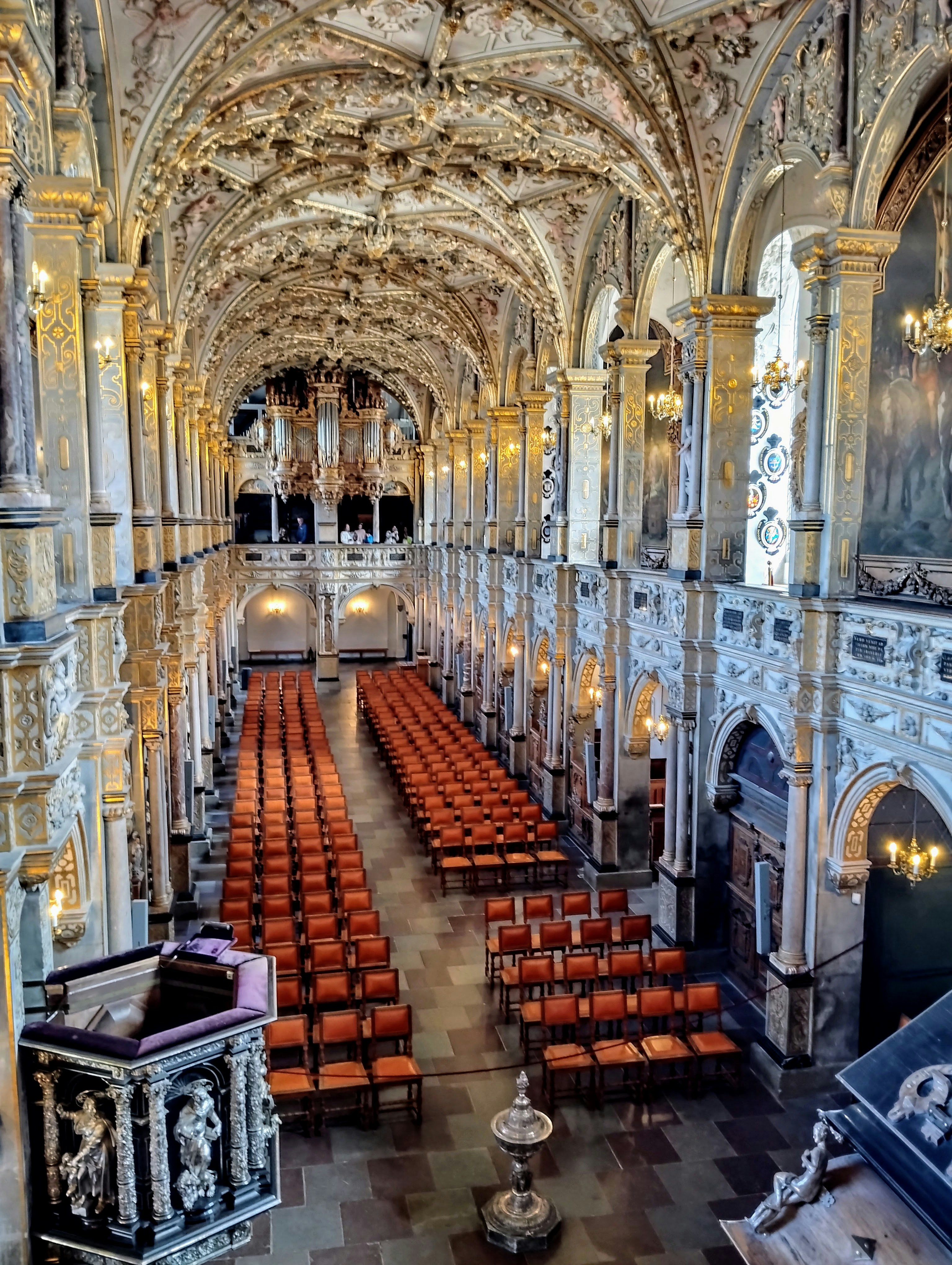 Ornate church interior with rows of orange chairs