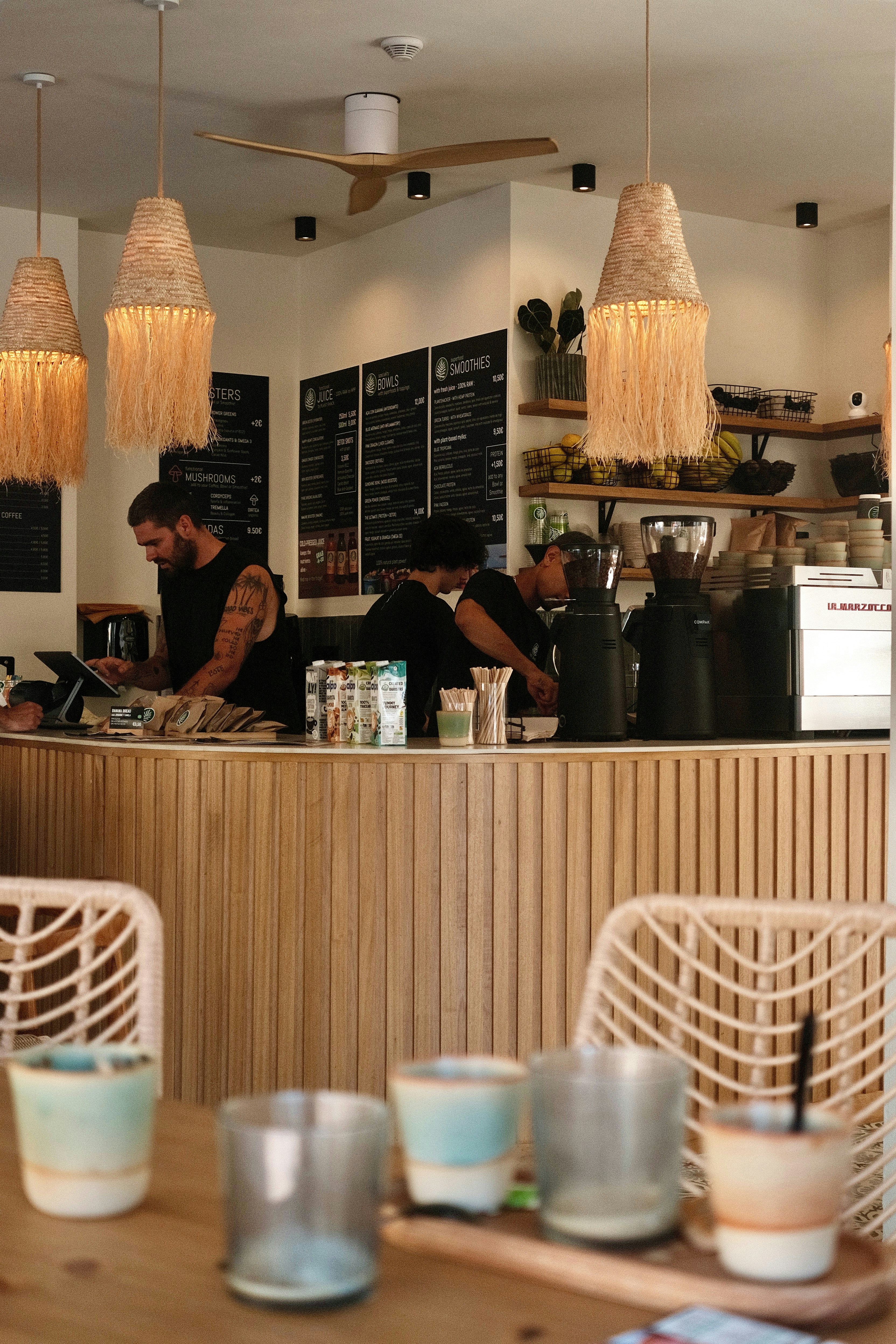 Coffee shop | Baristas working behind a wooden counter in a cafe.