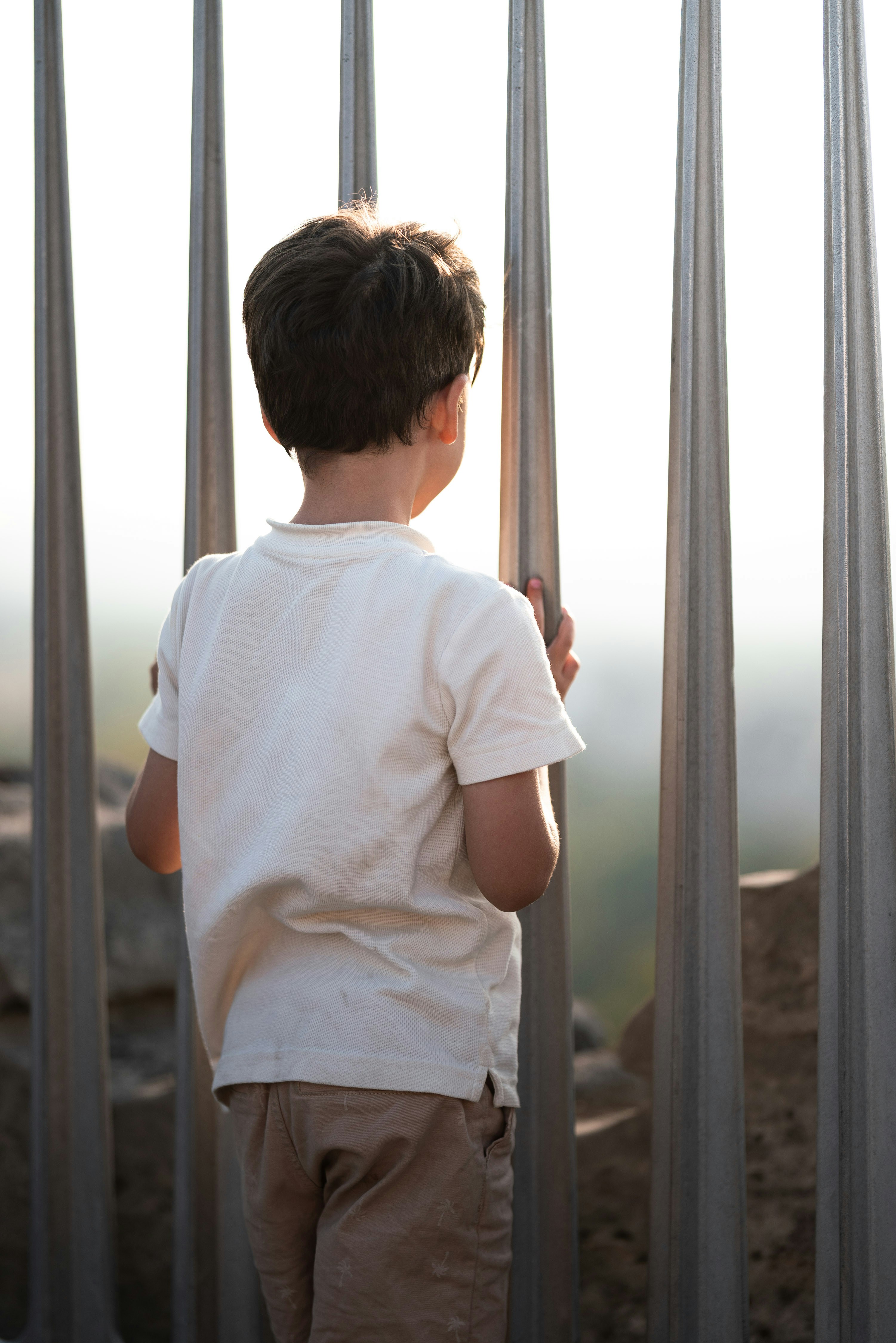 Young boy looking through metal bars photo – Free Portrait Image on ...