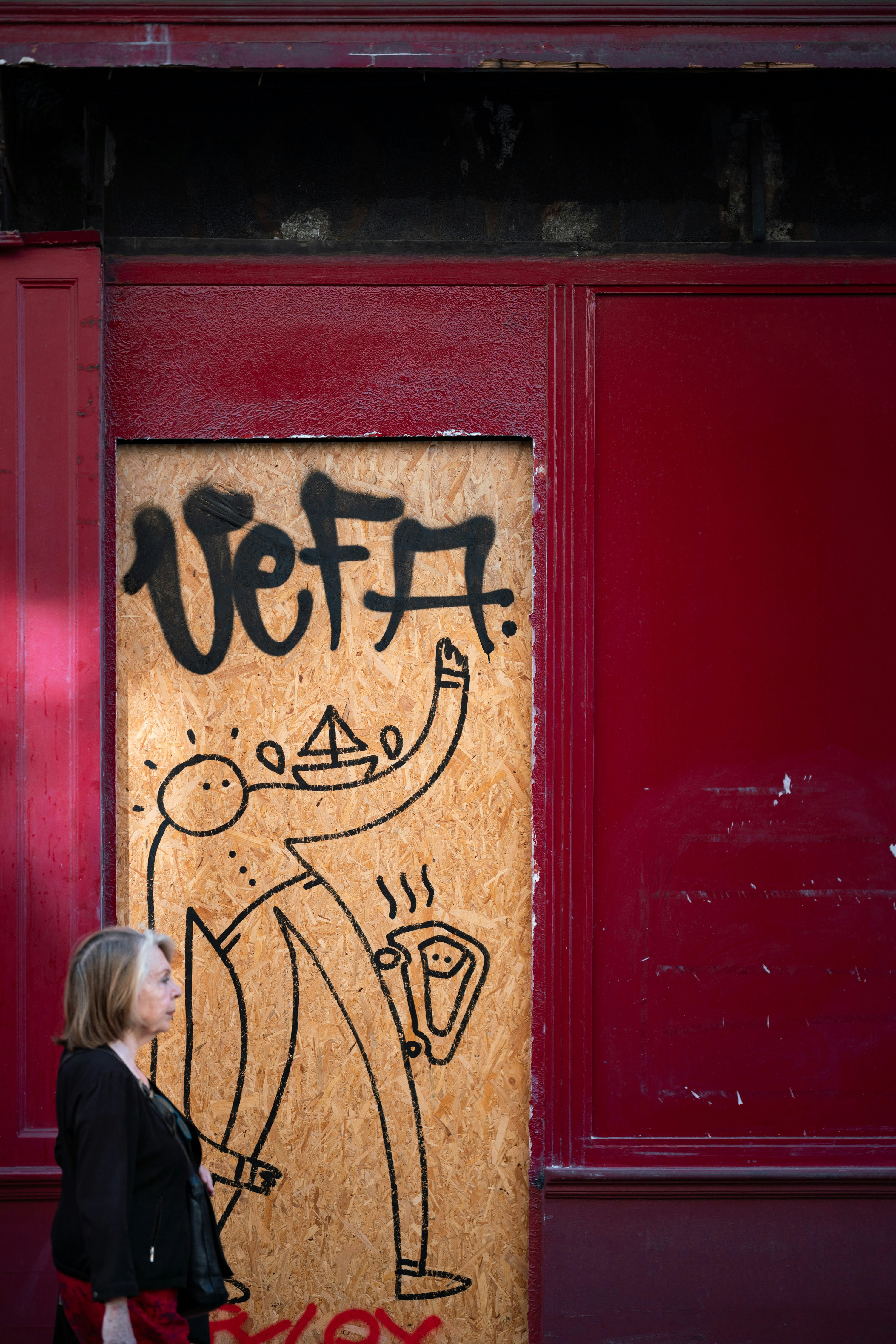 Graffiti art on a boarded-up storefront with a person walking by