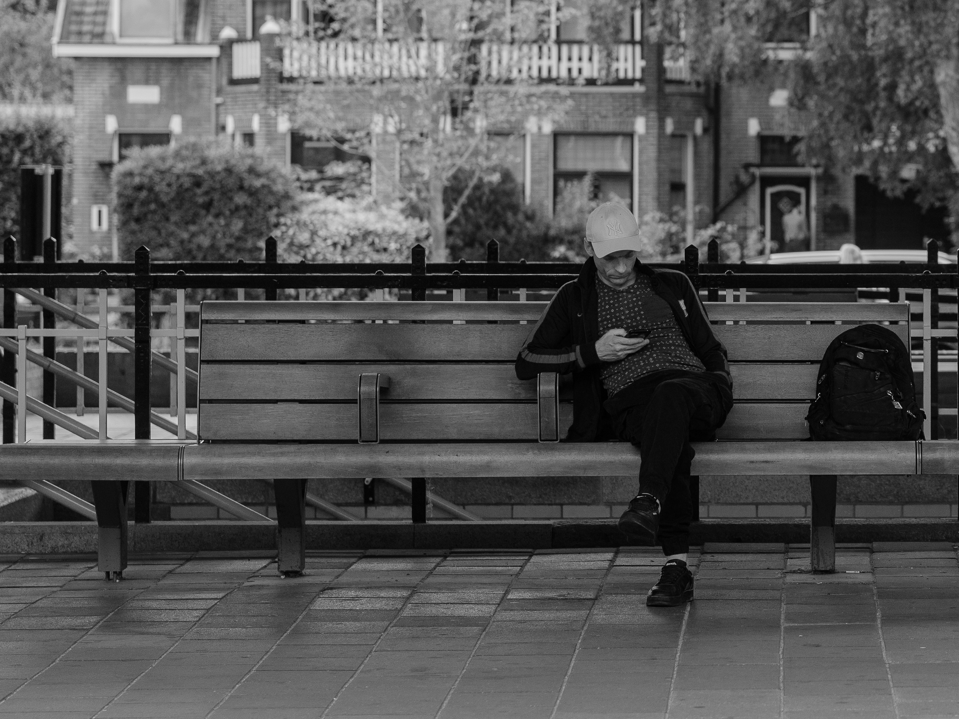 Waiting.. | Person sitting on a bench looking at phone.