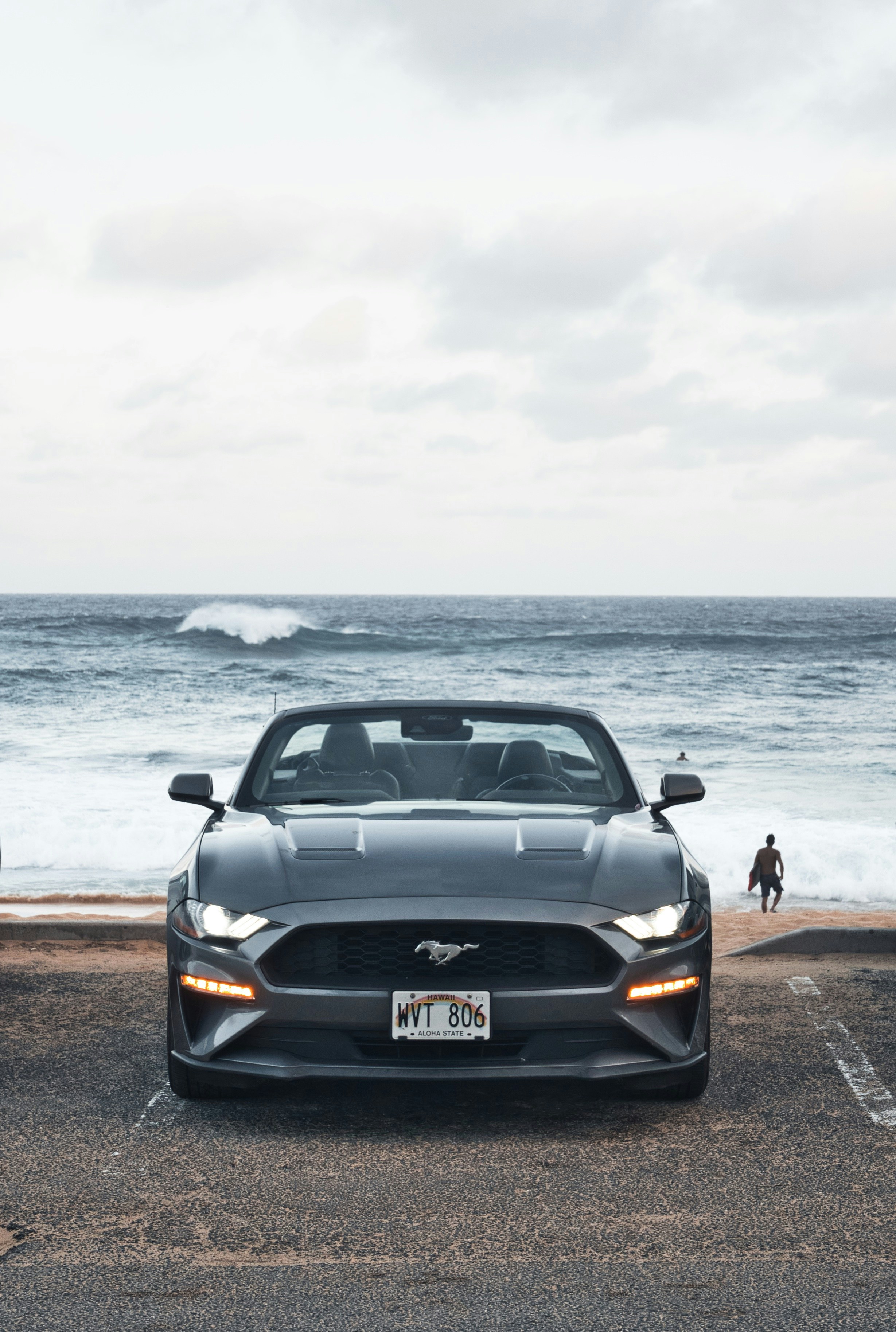 Gray convertible parked by the ocean with waves
