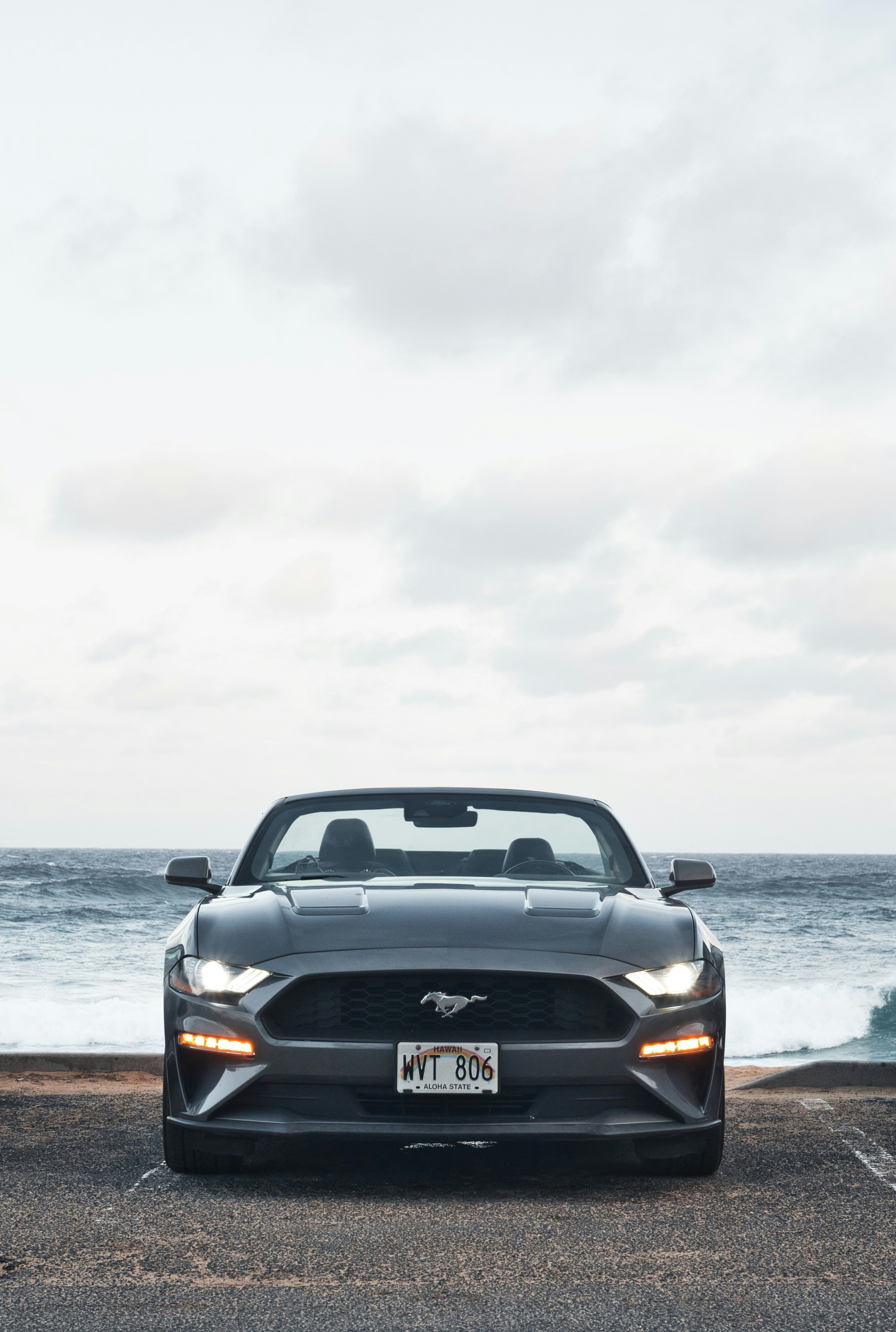 Gray convertible mustang parked by the ocean.