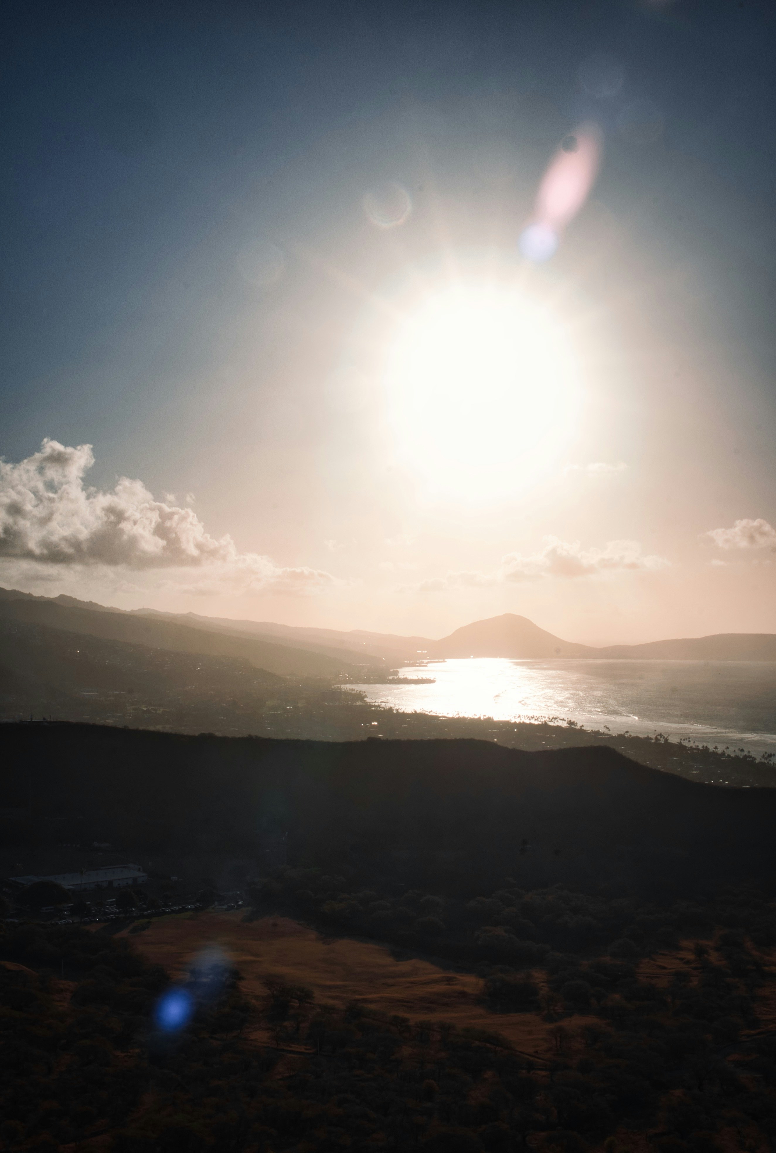 Sun shining over a calm lake and mountains.