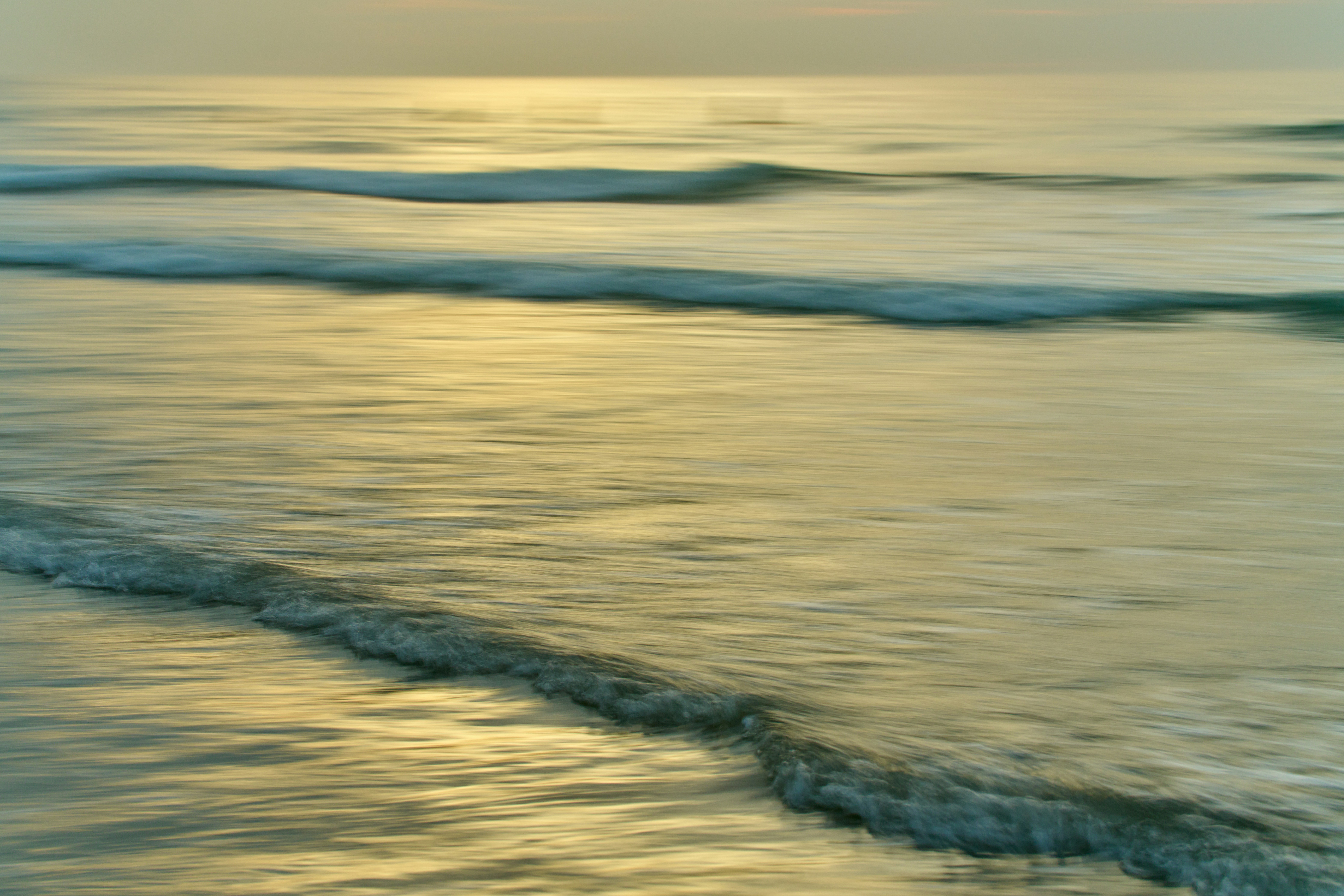 Gentle waves caressing the shore, reflecting soft hues of twilight in a serene coastal scene.