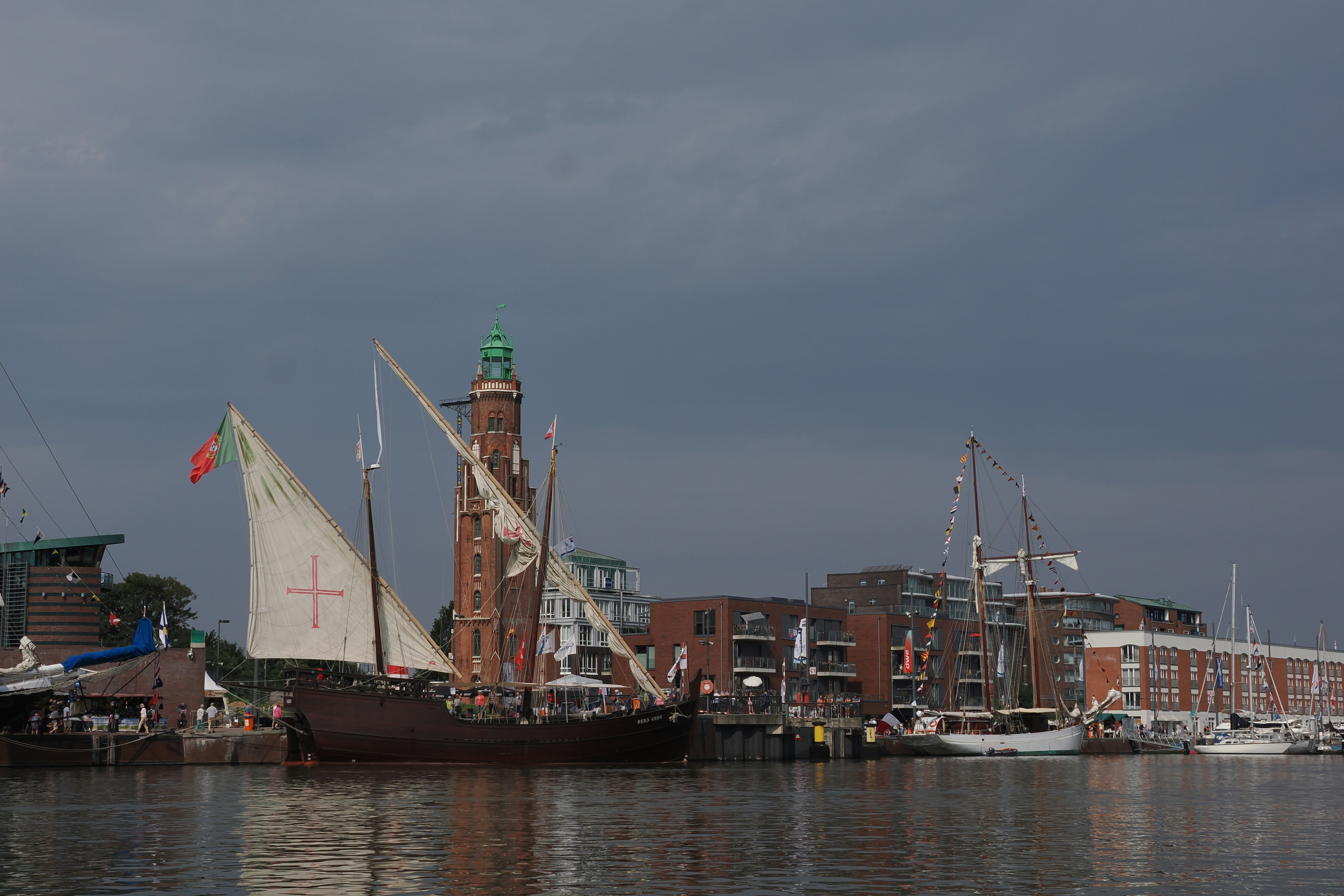 Eindrücke von der SAIL 25 in Bremerhaven | Historic sailing ship docked in a harbor with buildings.