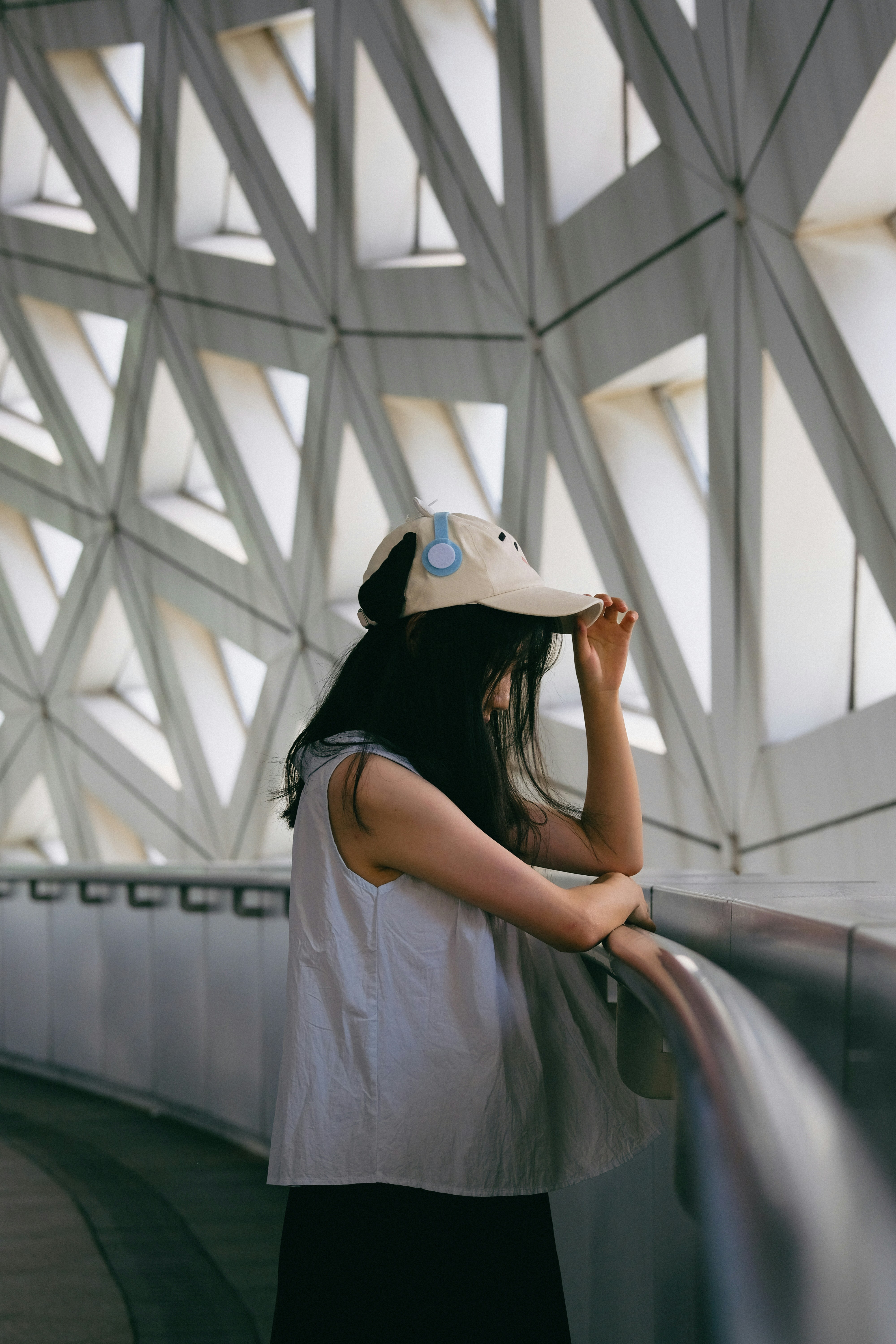 Woman in cap leaning on railing in modern structure