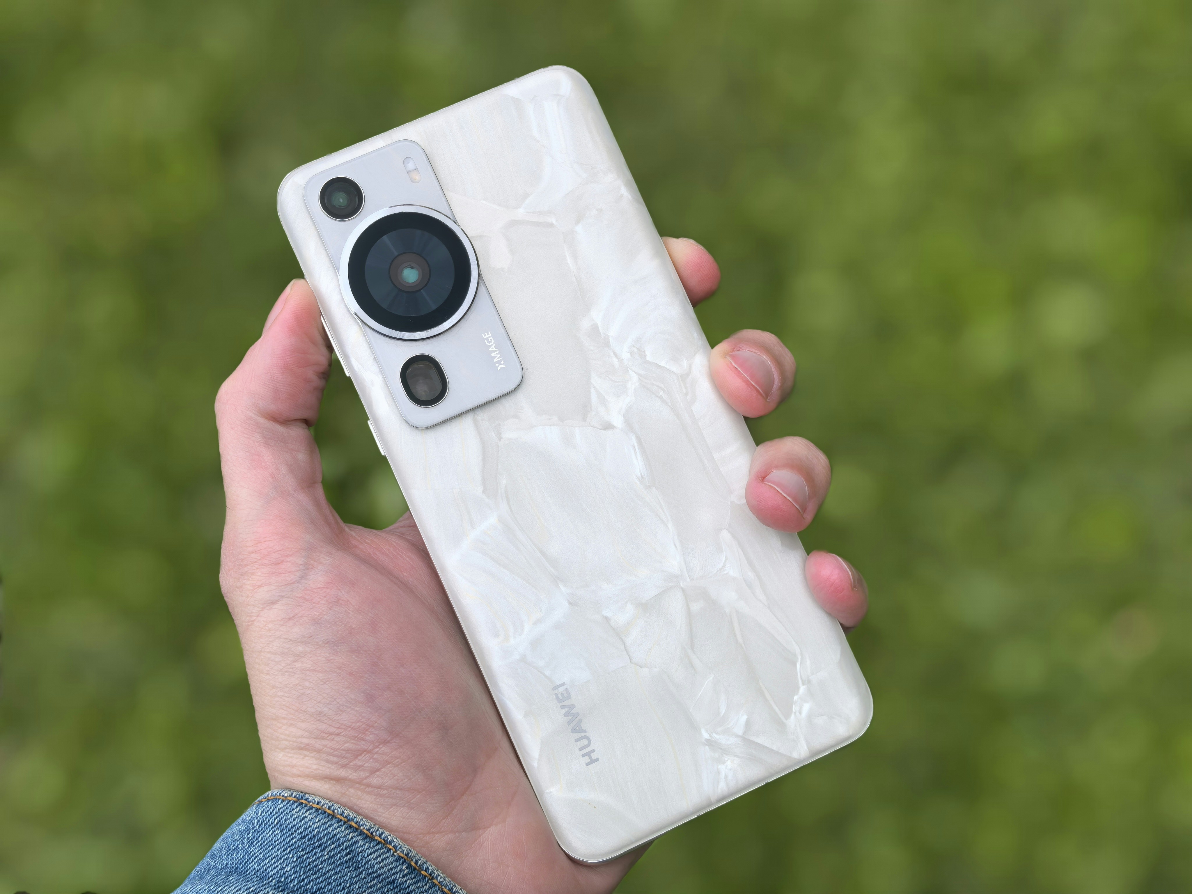 Hand holding a white smartphone with a marble pattern.