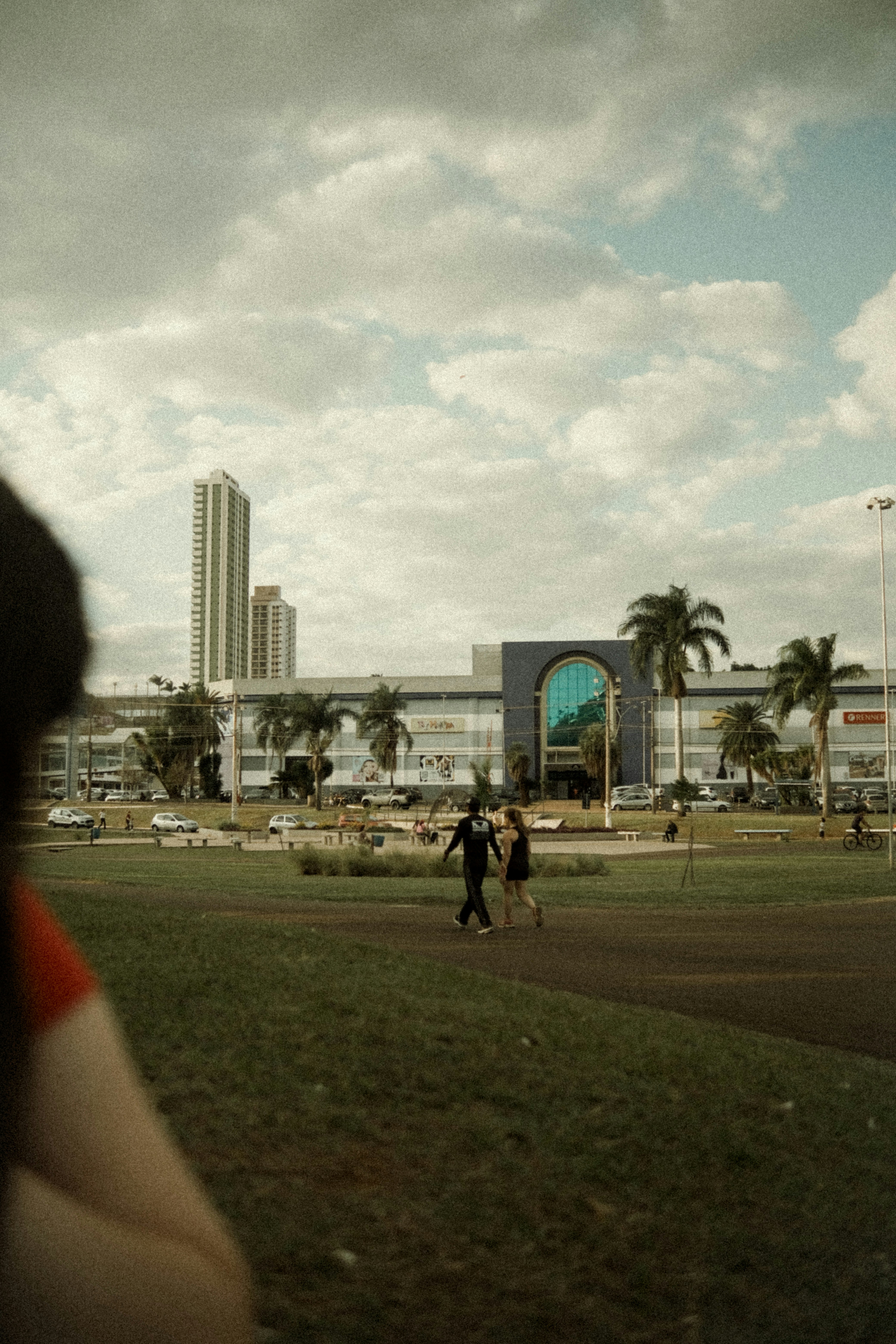 Couple walks near a large building with palm trees.
