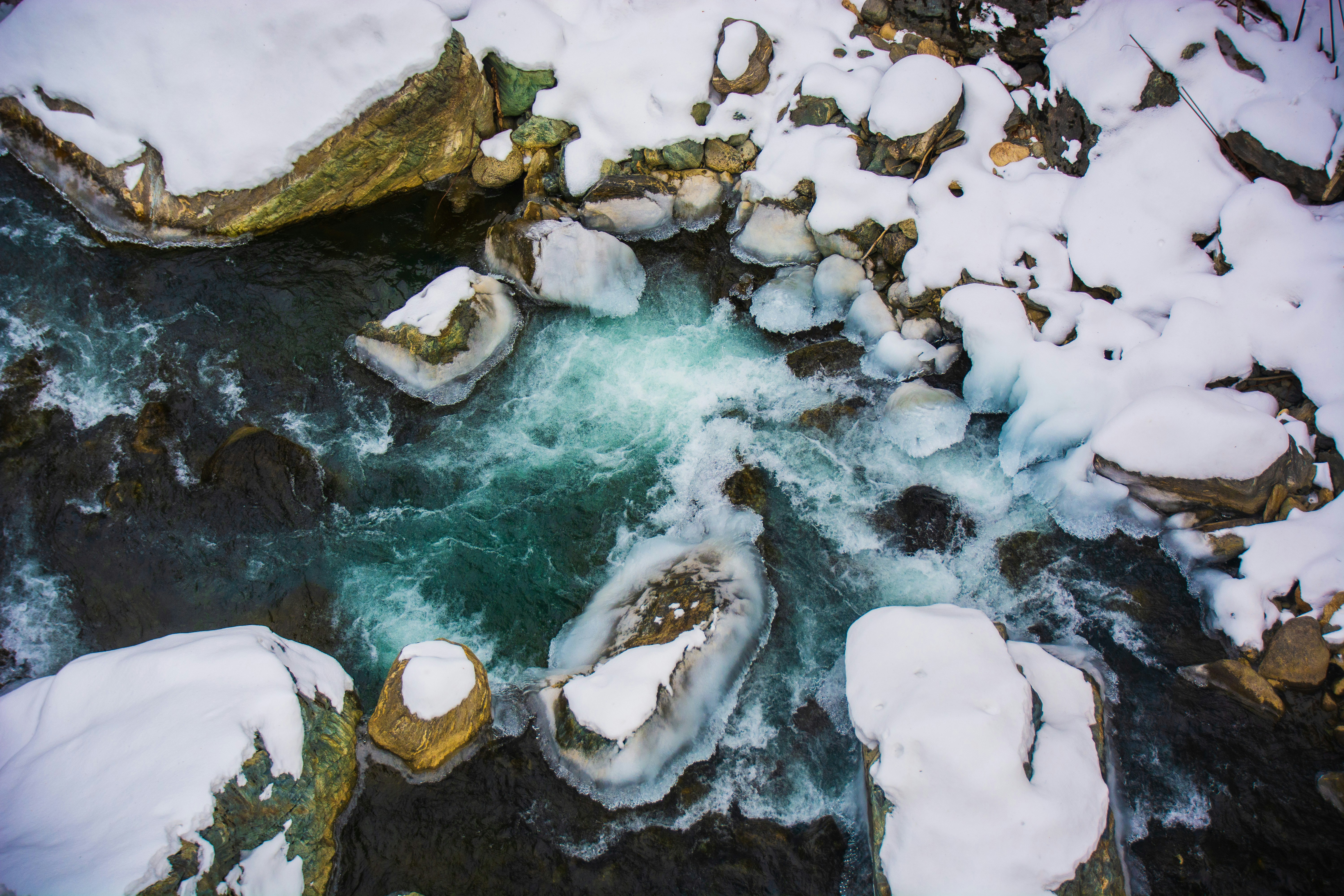 A cold river flows through snow-covered rocks