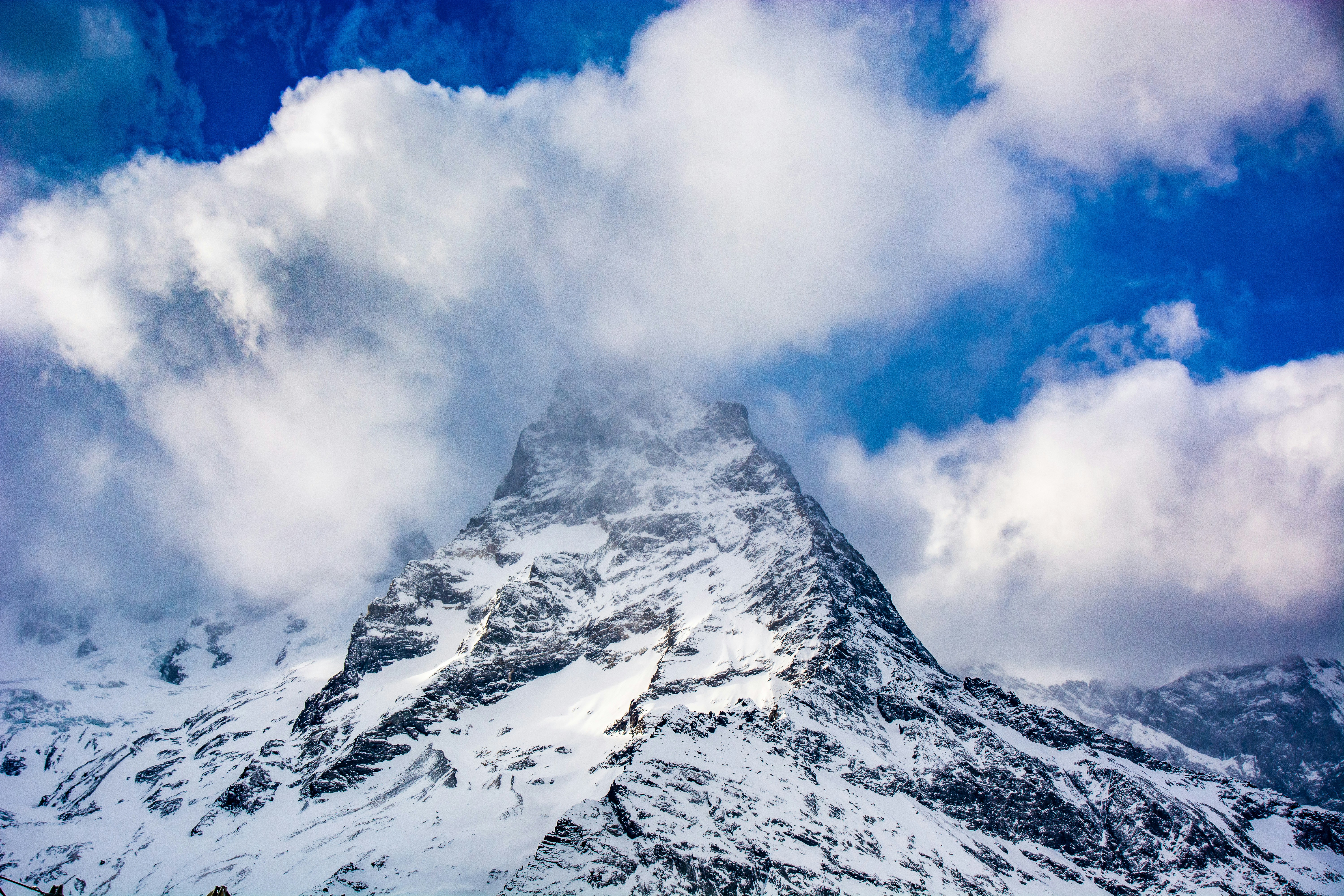Majestic mountain peak partially shrouded in clouds, showcasing a winter landscape with snow-covered slopes.